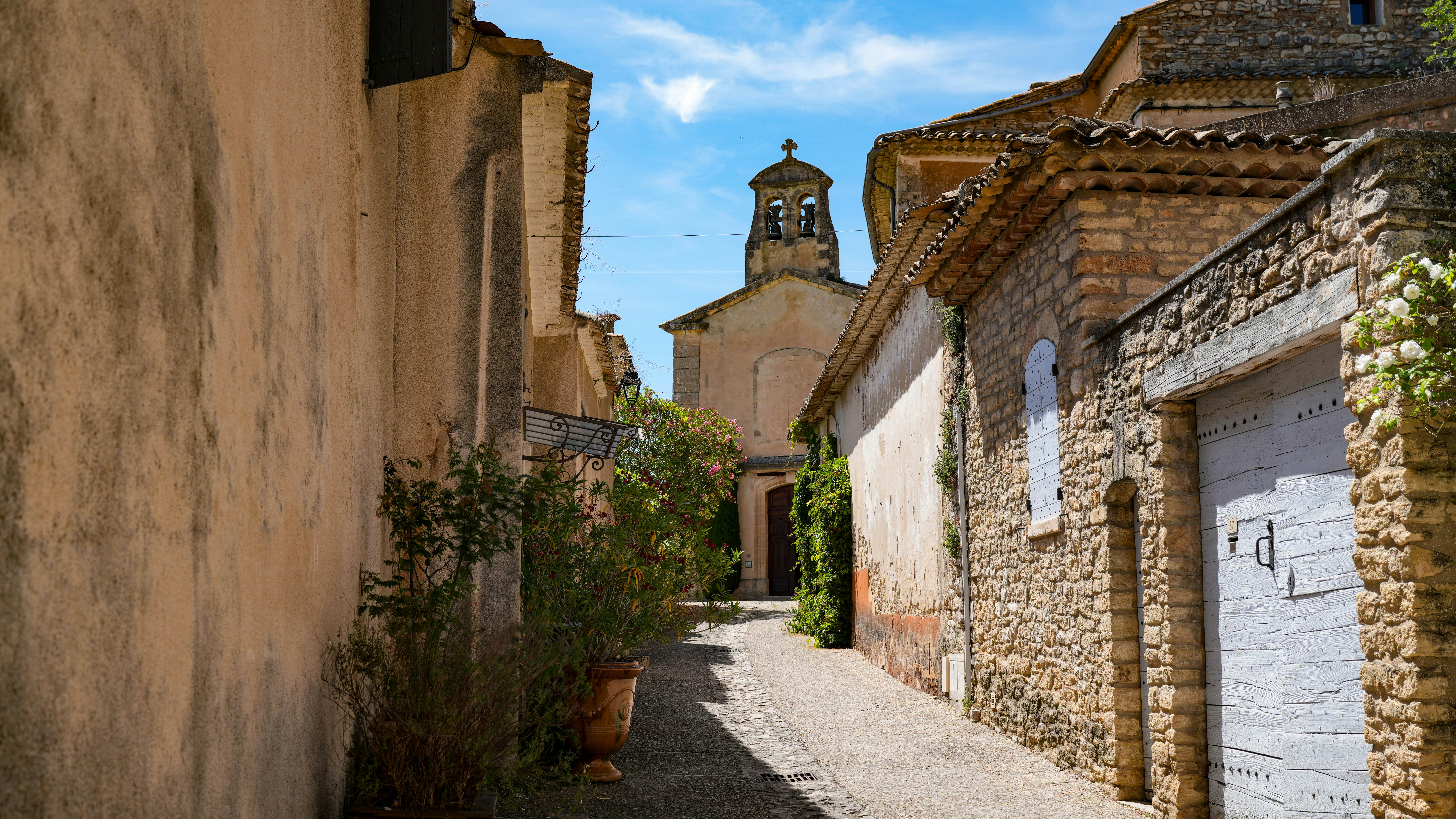 Quiet Mediterranean Street with Stone Facades and Distant Bell Tower