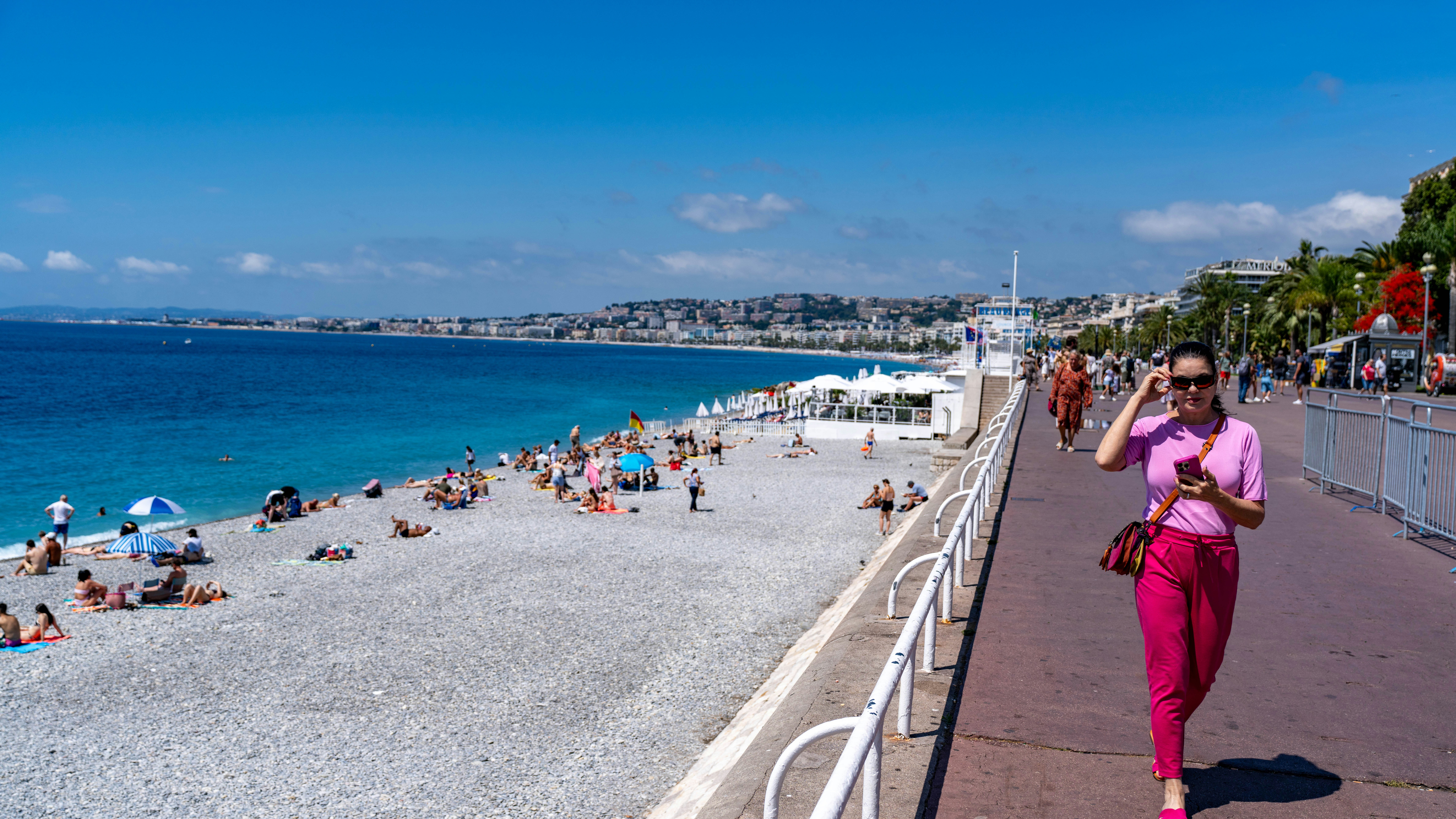 Sunny Promenade: A Woman in Magenta Walks Along the Seaside Boardwalk
