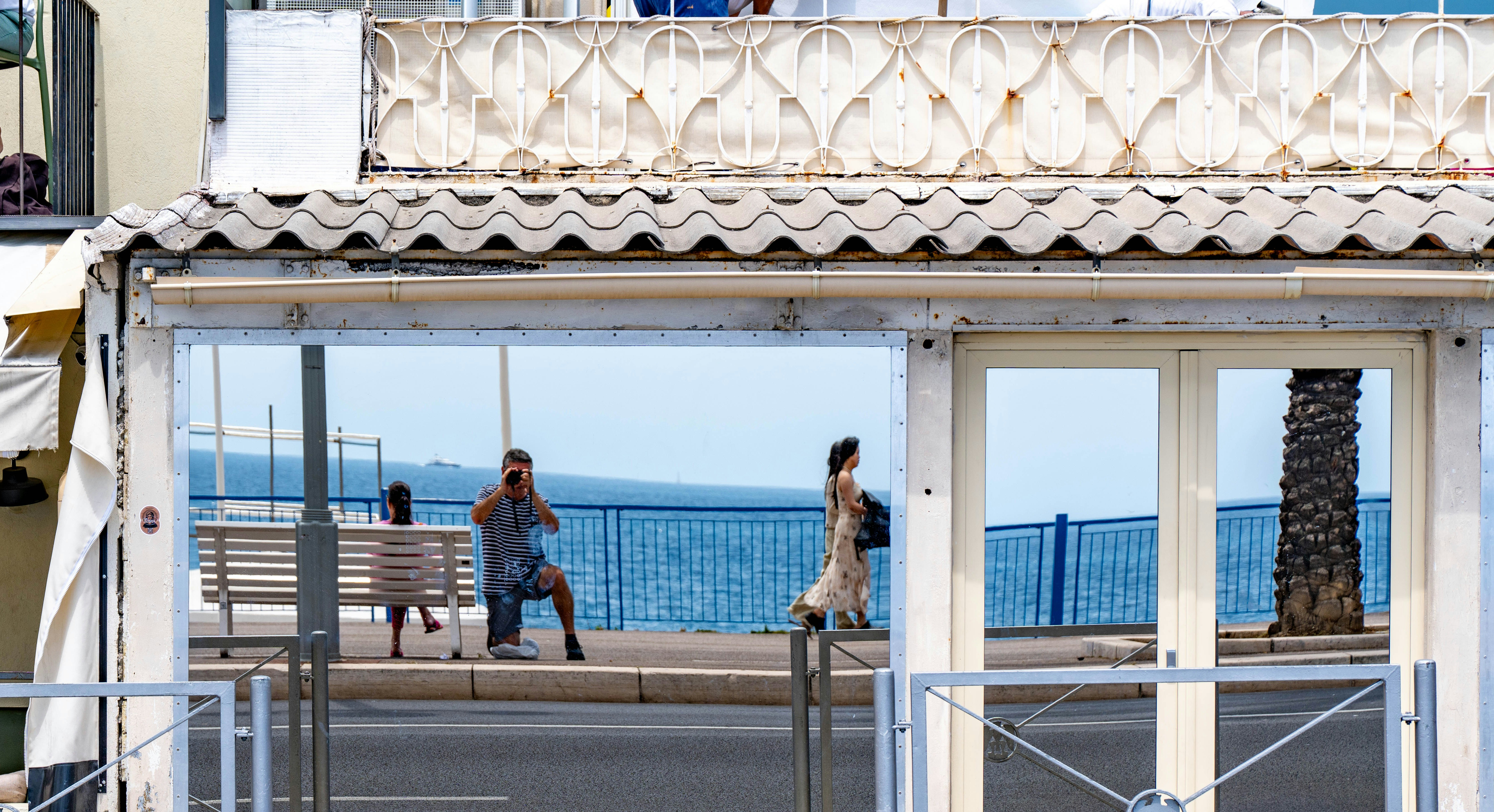 Seaside Boardwalk in Frame: Tourists and Ocean Vista Through a Shuttered Corridor