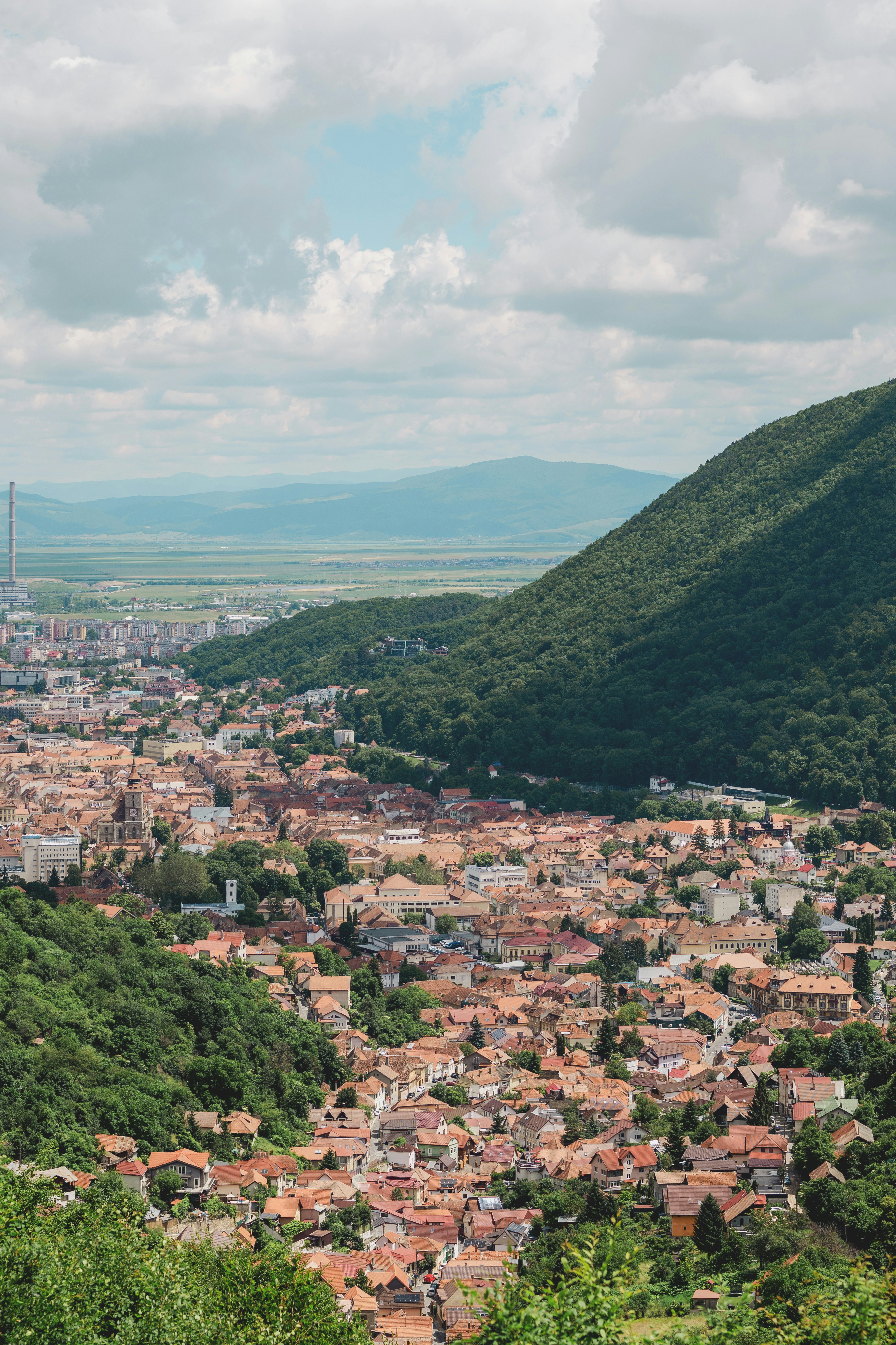 Urban valley beneath a green ridge under a sky of soft cumulus