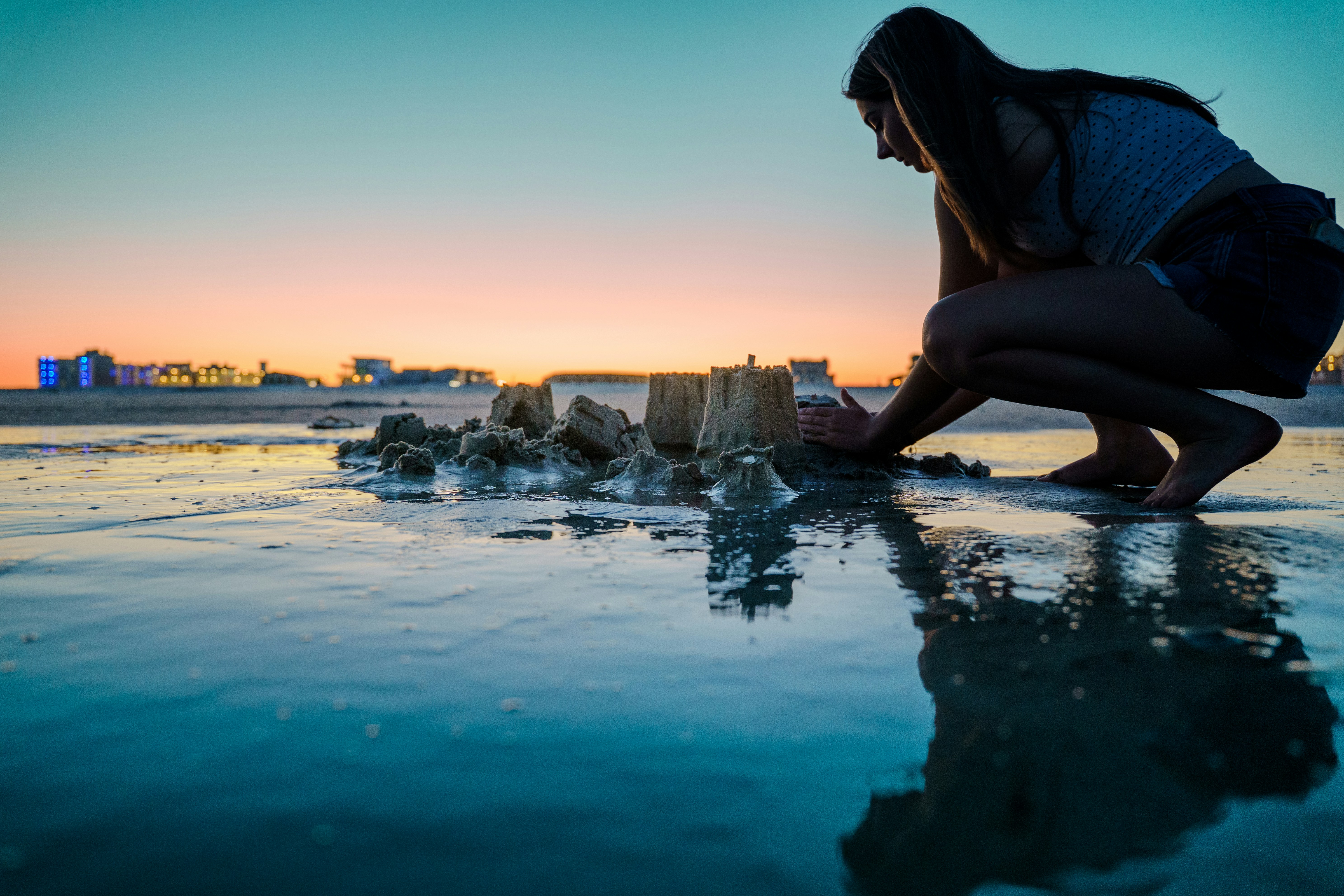 Silhouette by the Tidal Mirror: A Girl at Dusk Crafting Sandcastles