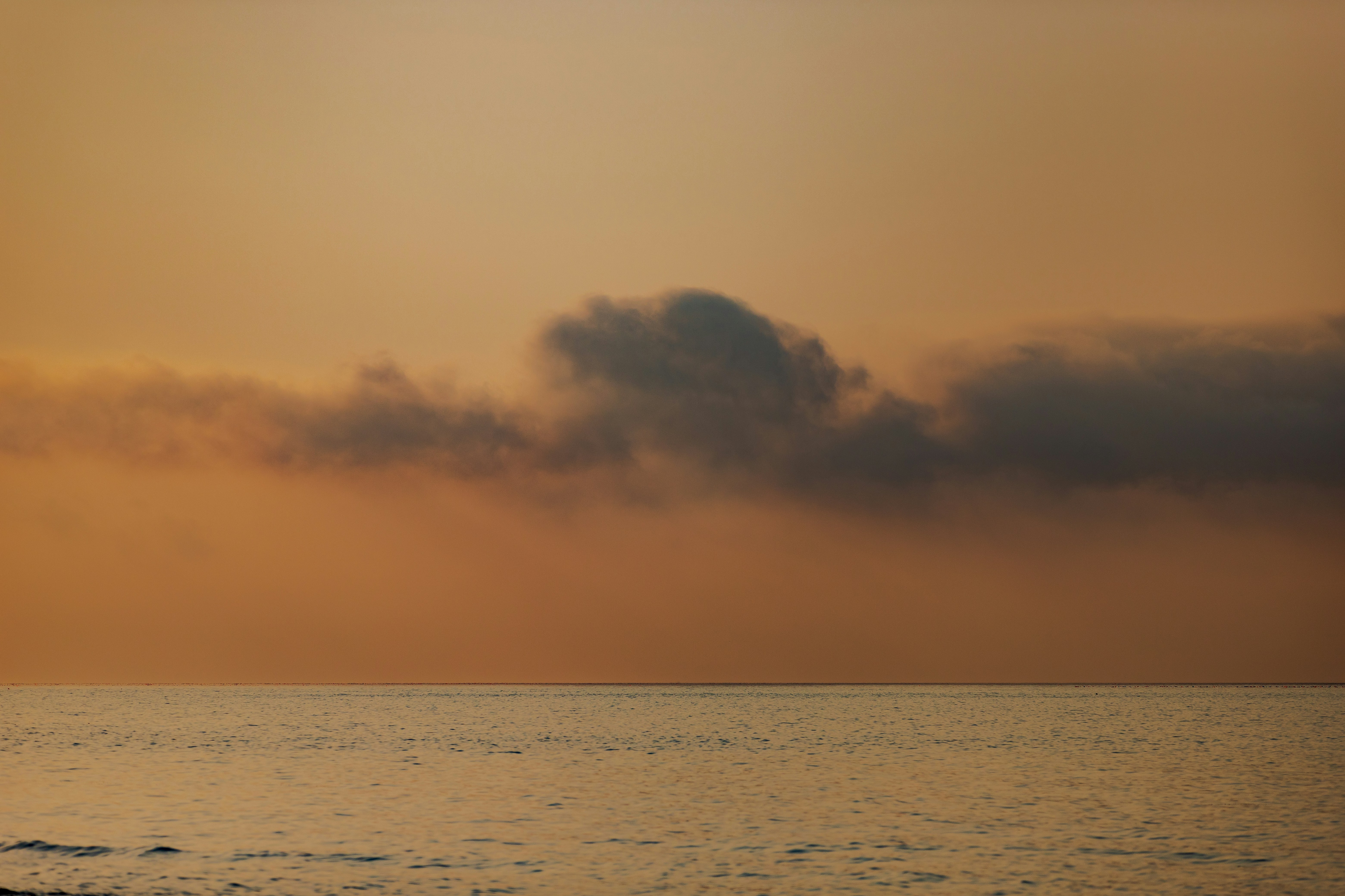 Muted Horizon: Clouds Velvet the Sunset over Calm Seas