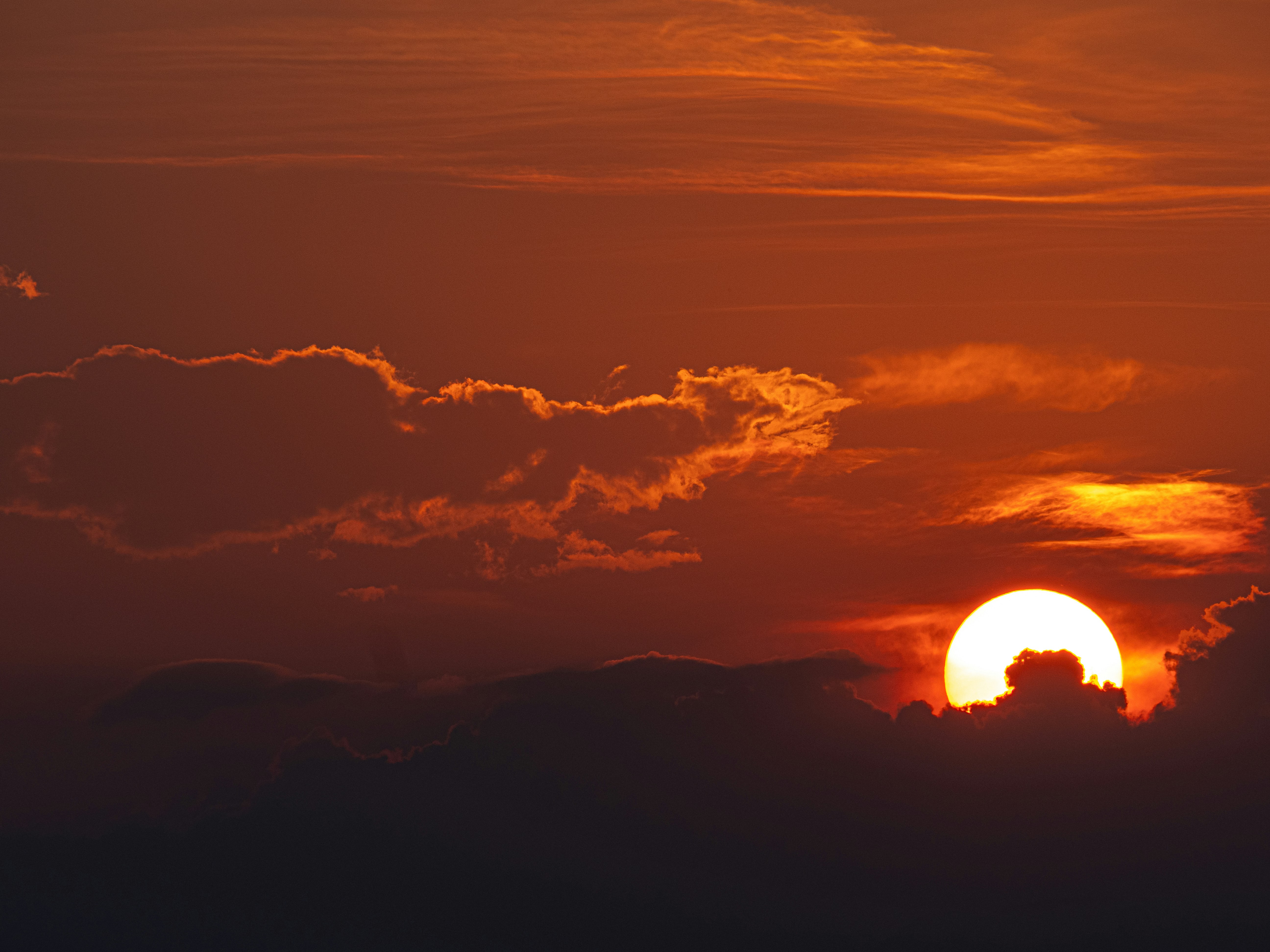 Low Sun, Quiet Horizon: A Fiery Dusk Over Darkened Clouds