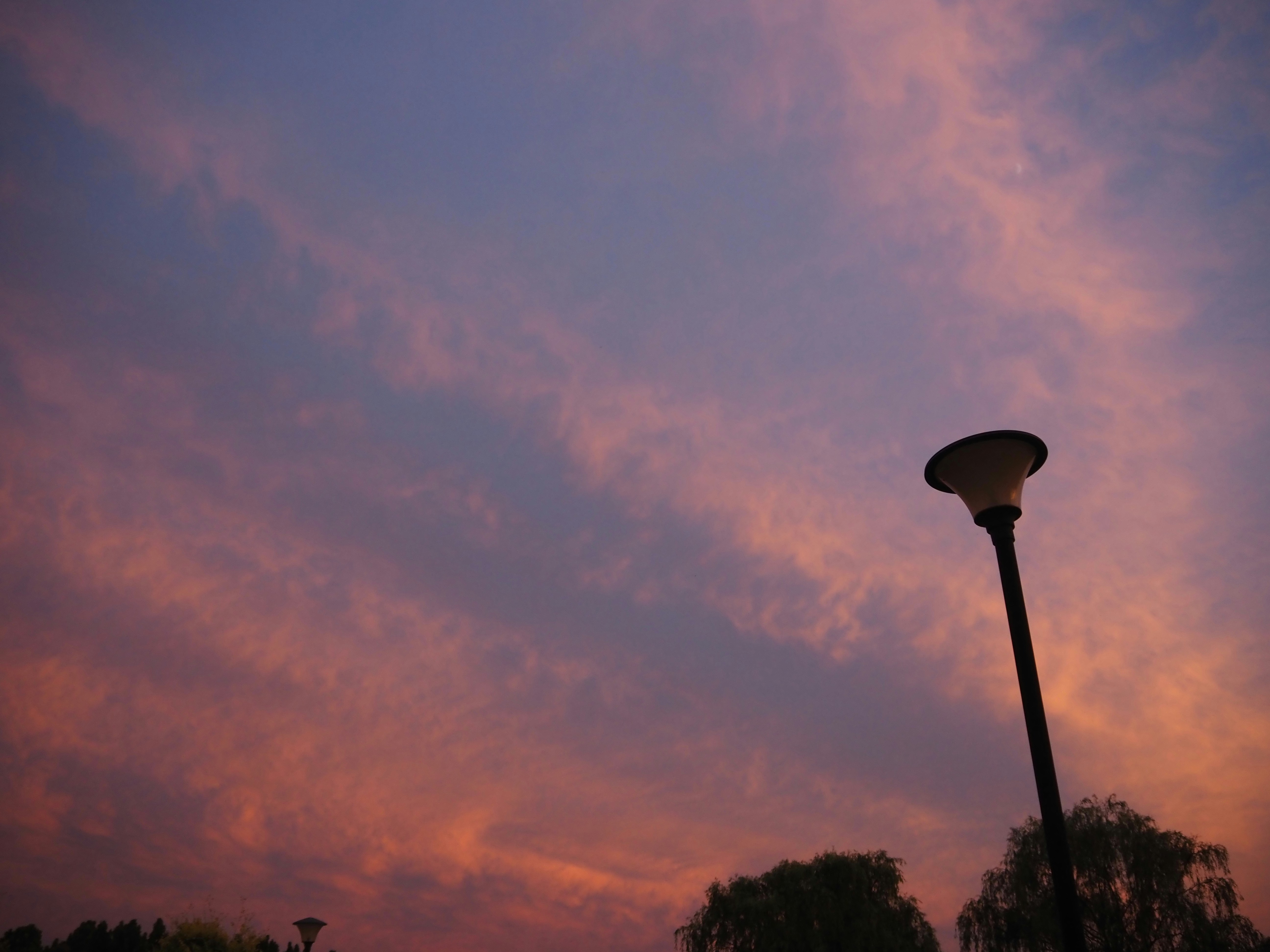 Amber Sky Over Quiet Park: A Sunset Glow Behind a Lone Street Lamp