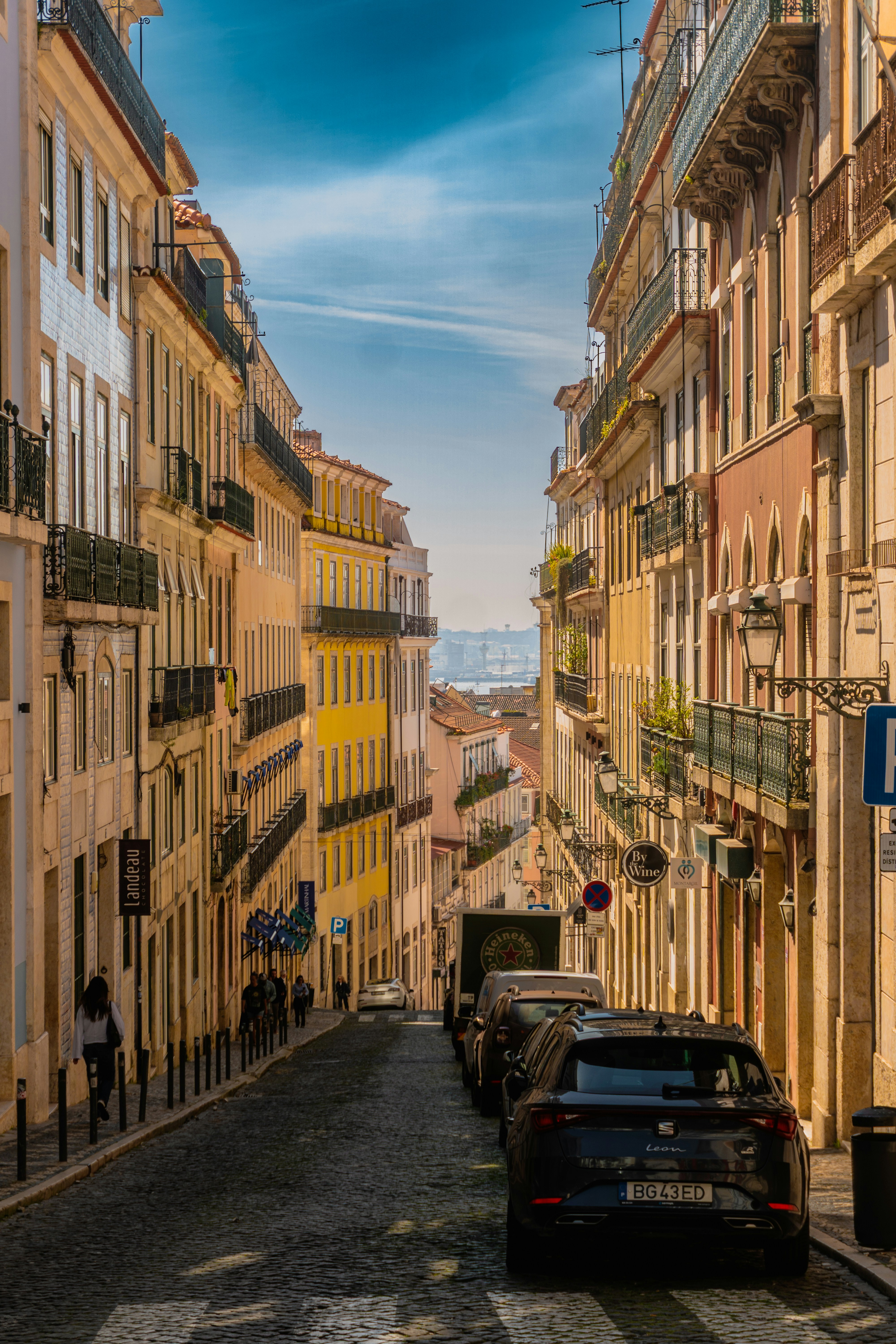 A Sunlit Calle: Cars, Steps, and Sky Framing a Lisbon Tilt