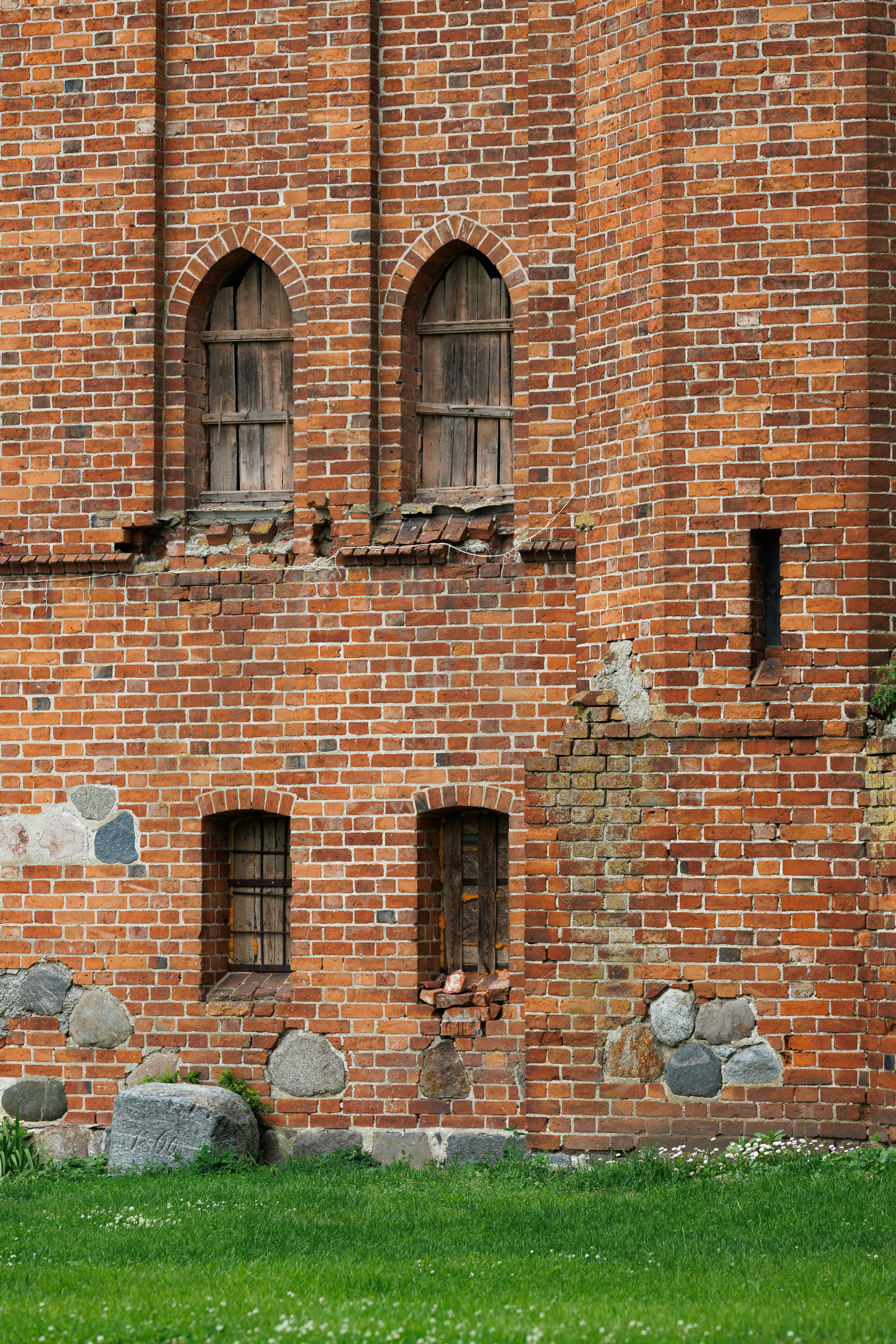 Weathered Brick Facade with Arched Windows and Stone Patchwork