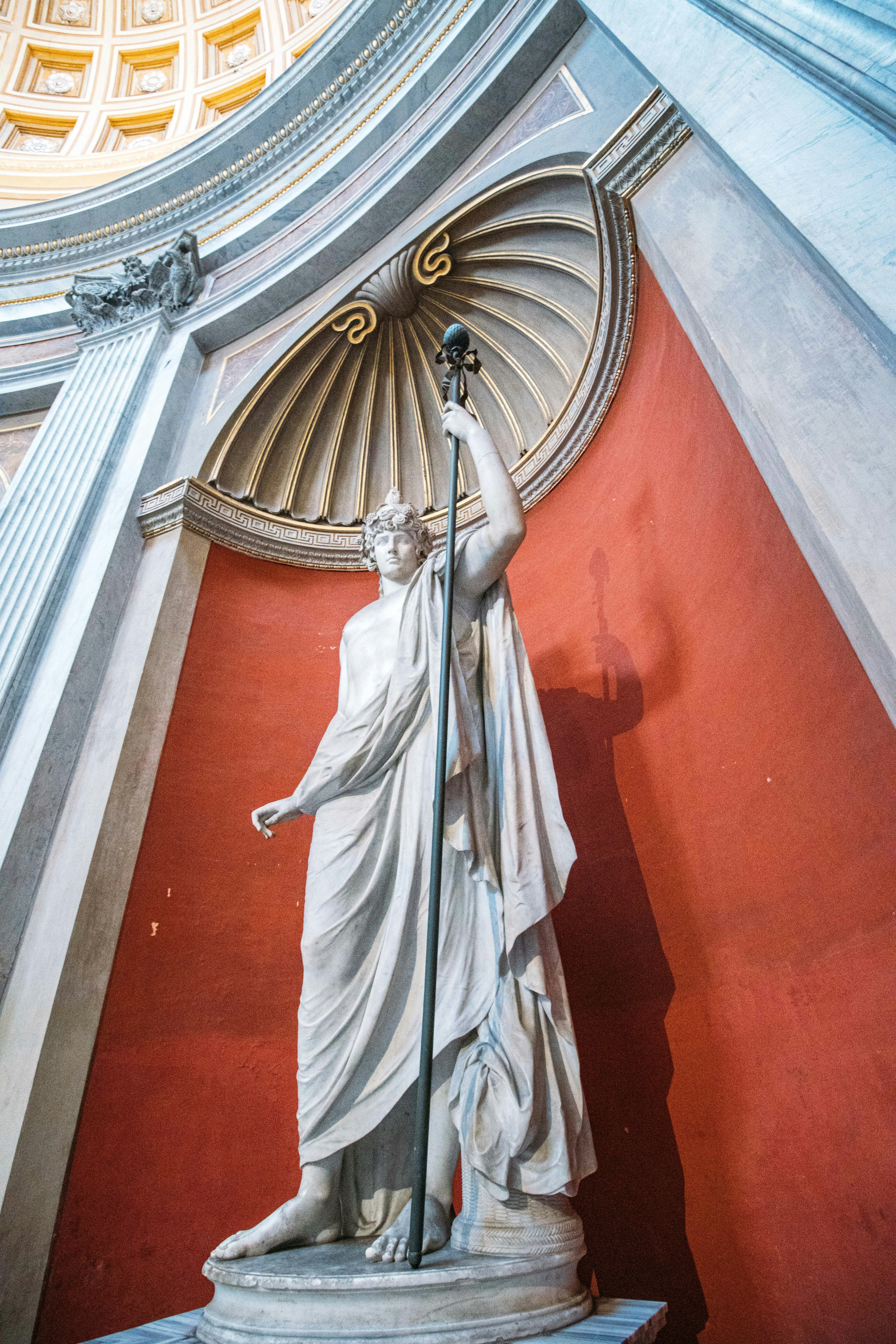 Statue of a Draped Figure Holding a Staff Beneath an Ornate Dome