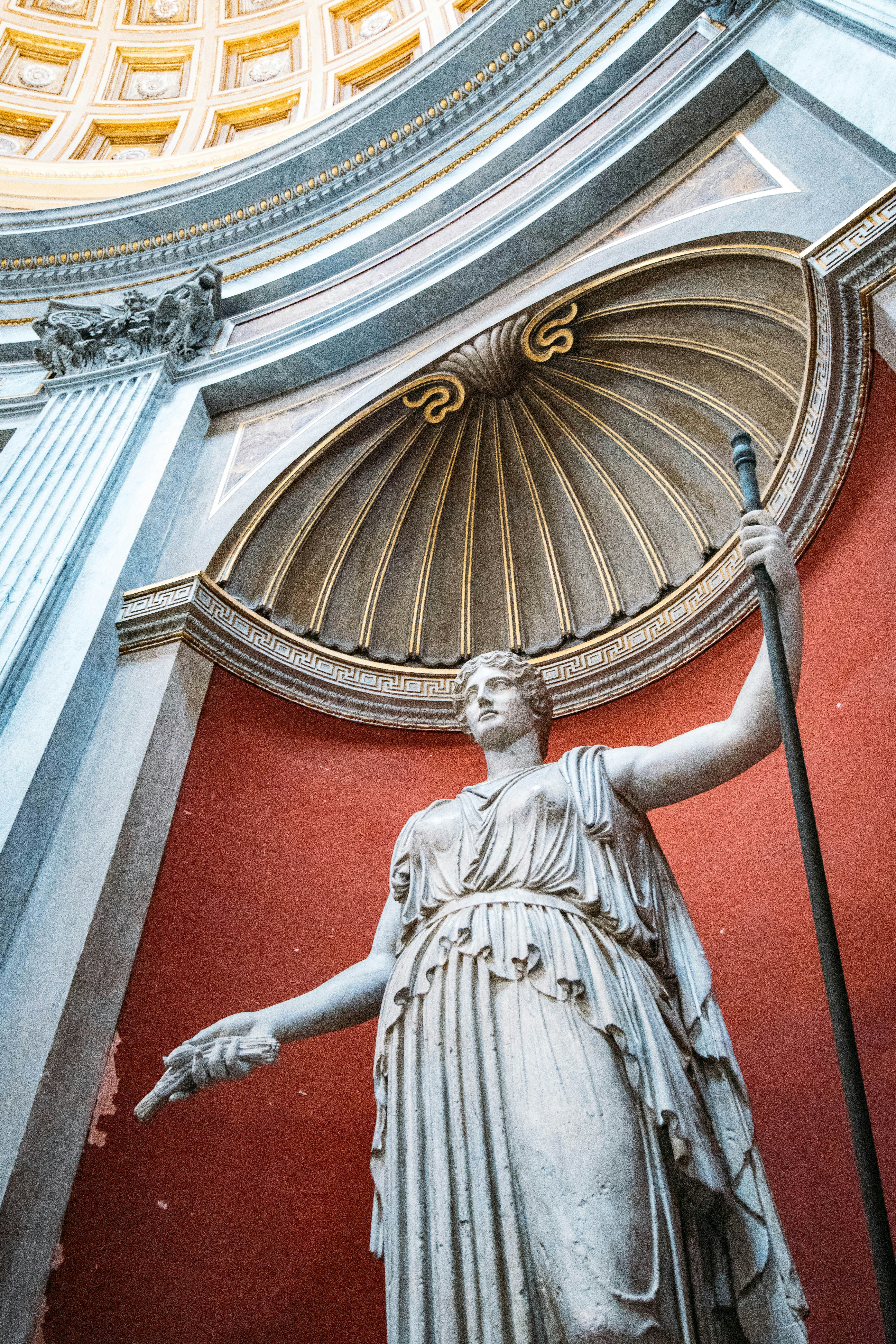 Gilded Dome and Sentinel: A Classical Statue Beneath Arching Grandeur