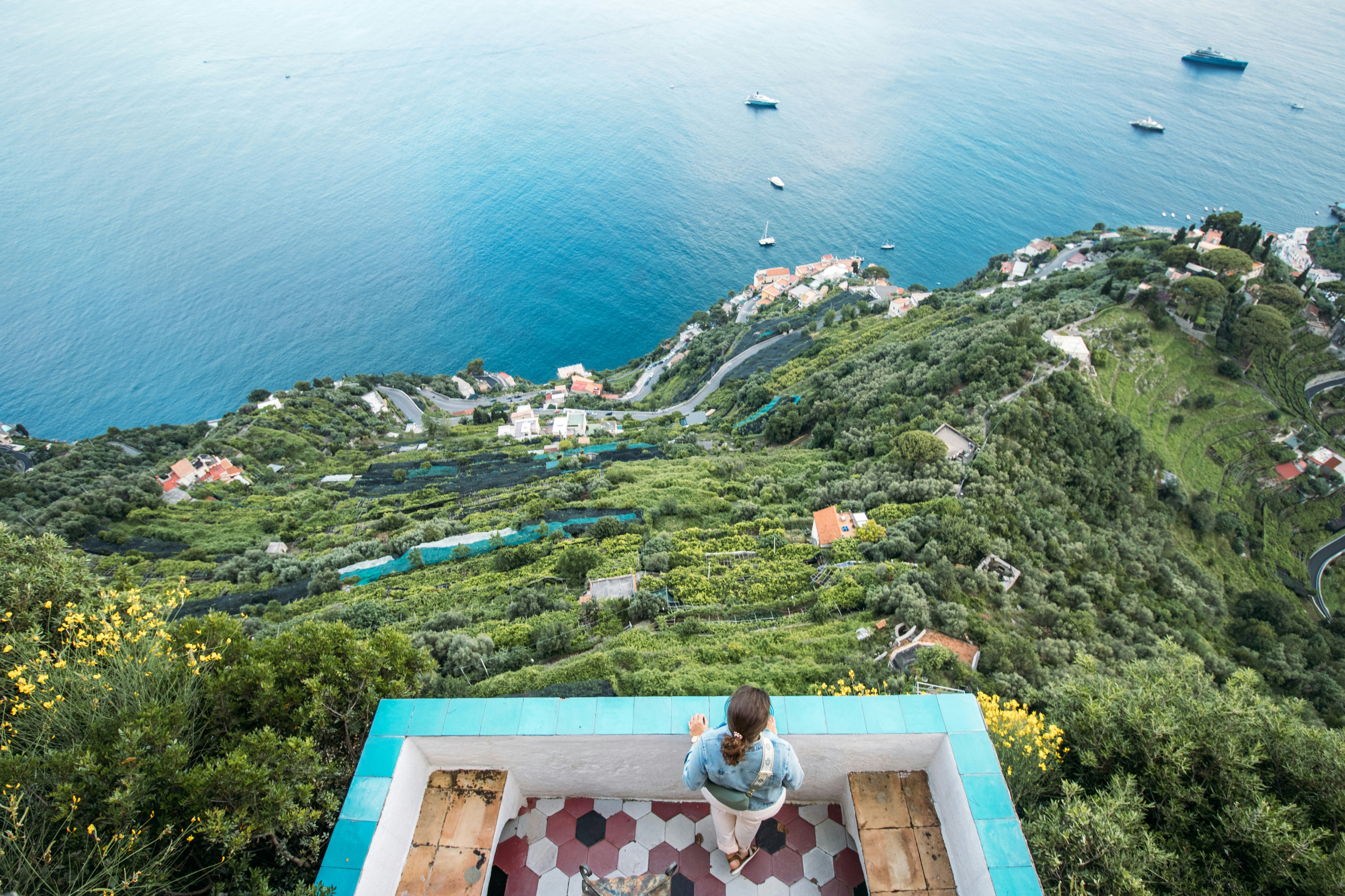 Clifftop Terrace: A lone spectator overlooking a turquoise ocean panorama