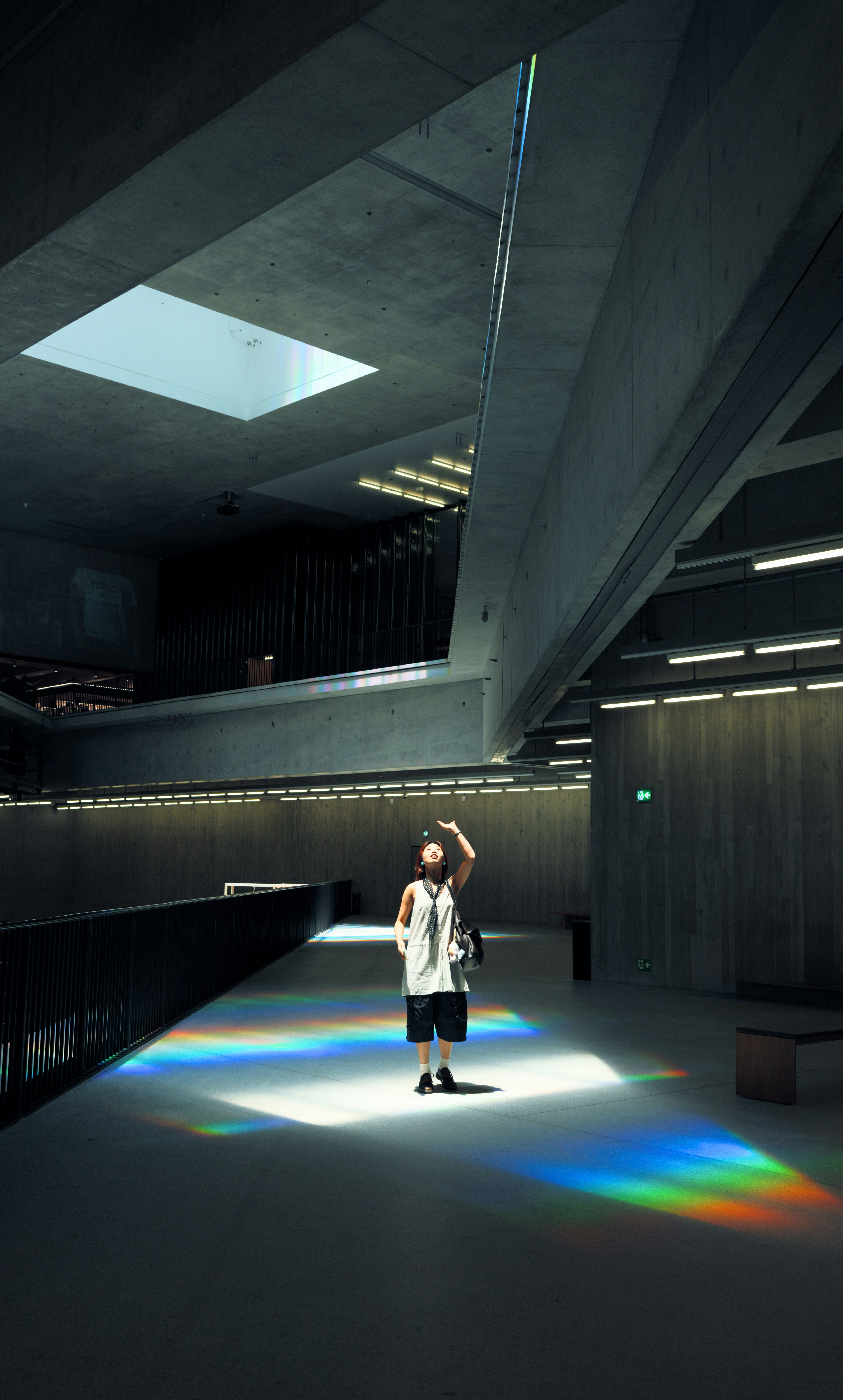 A solitary wanderer in a prism-lit concrete gallery