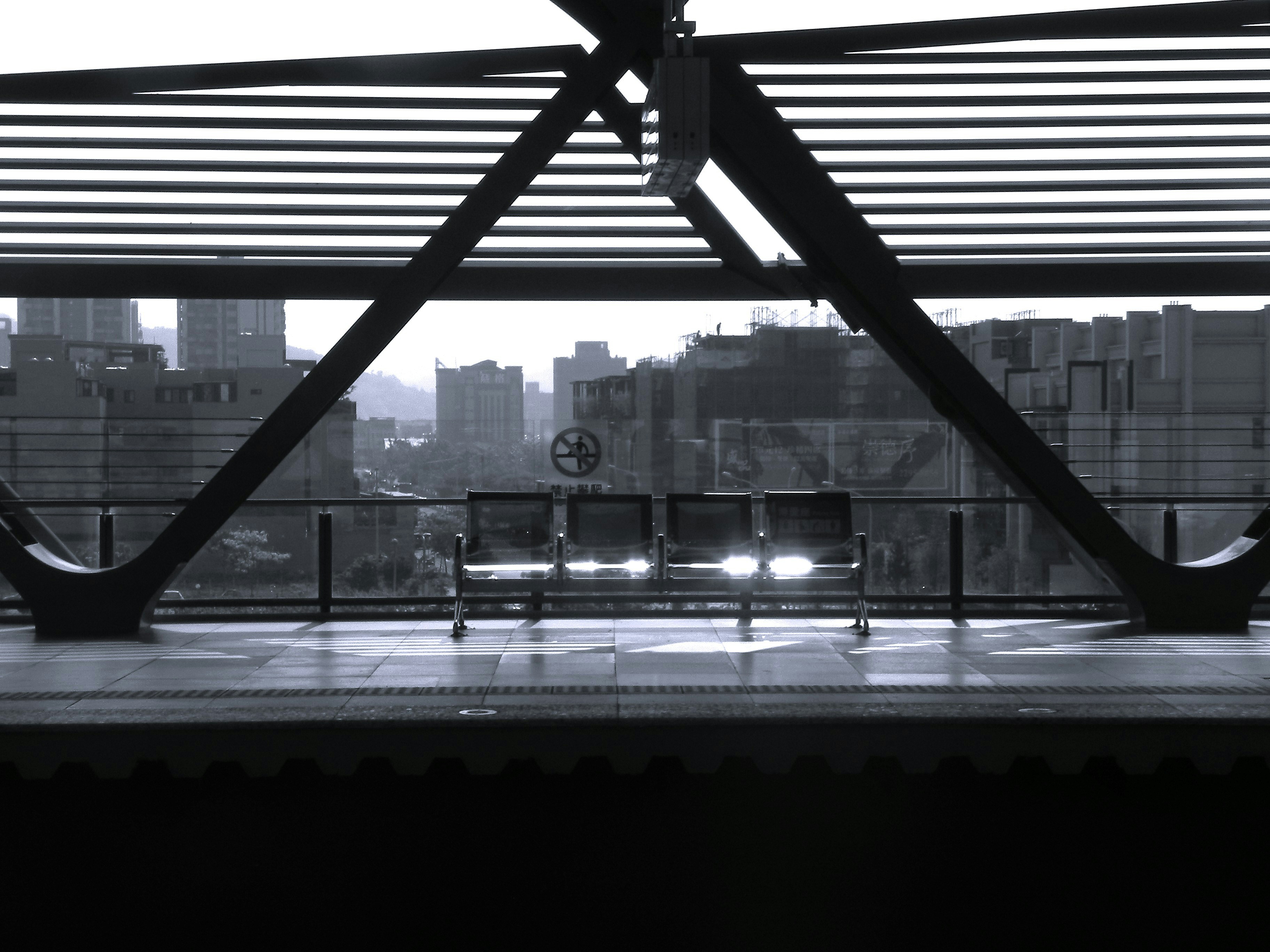 Crossed Struts Over a Cityscape: Quiet Geometry at the Platform Edge