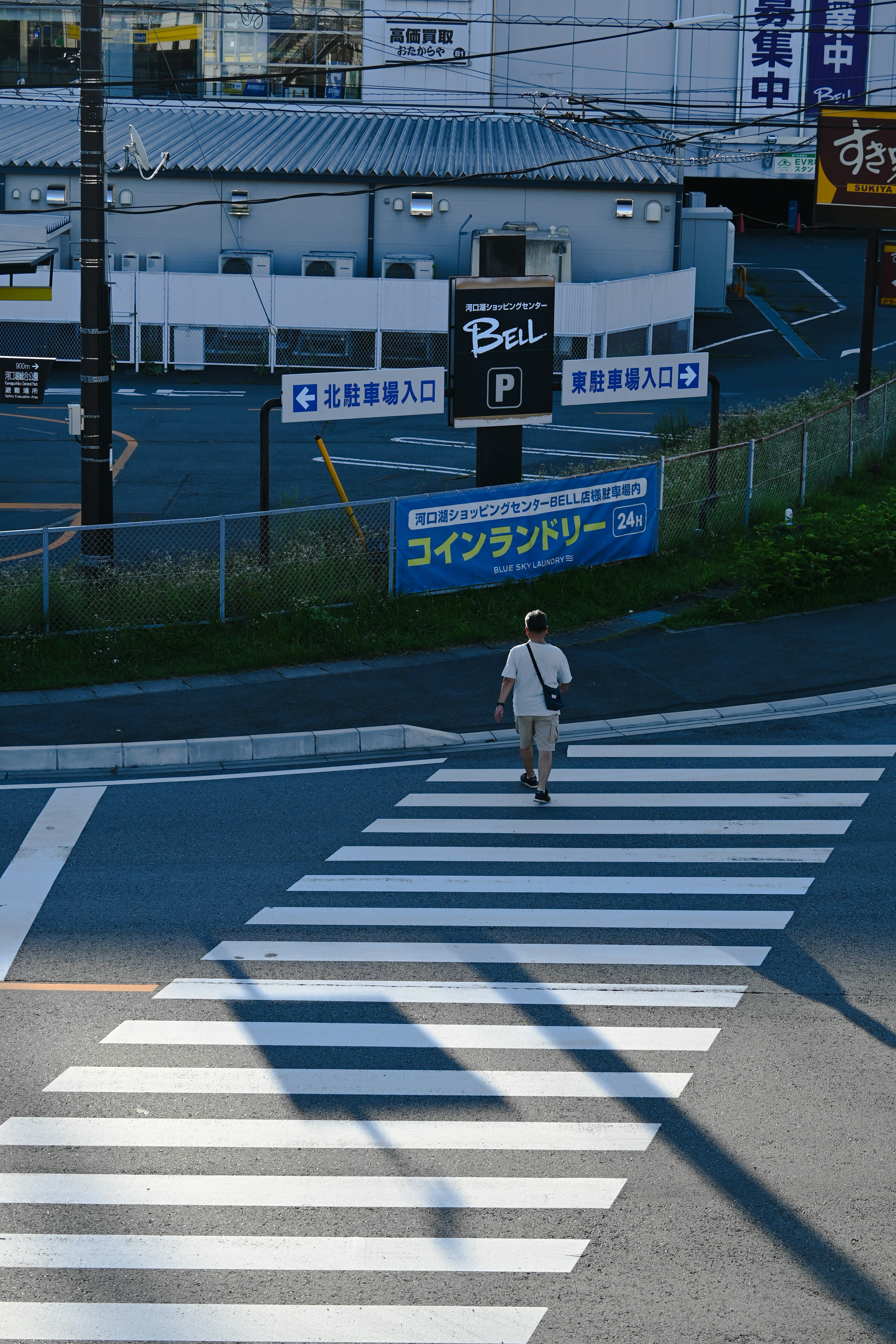 Crosswalk Moment: A lone pedestrian crosses into a neon-tinged streetscape