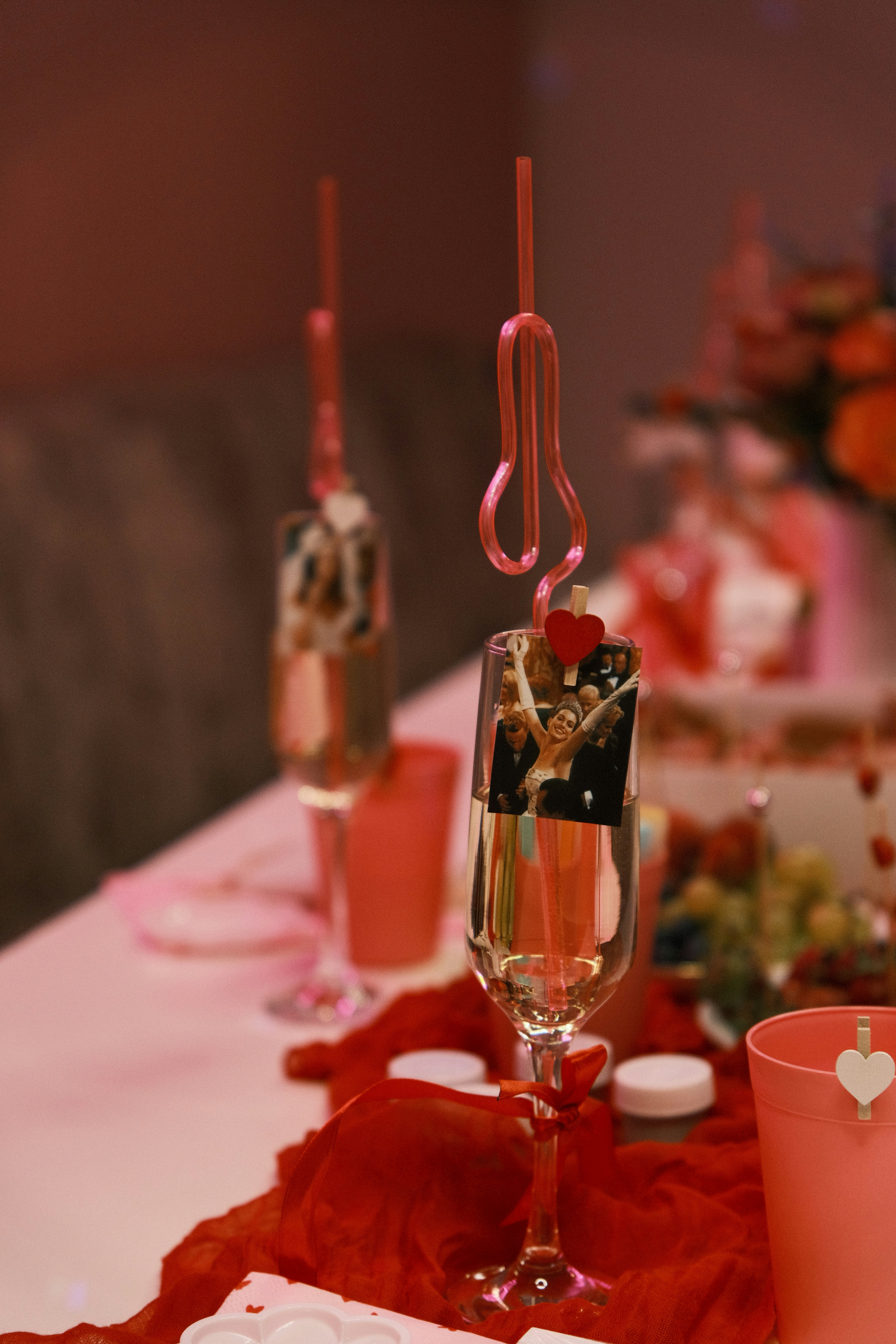 A Glass of Keepsakes: Hanging Photos and Red Accents at a Wedding Table