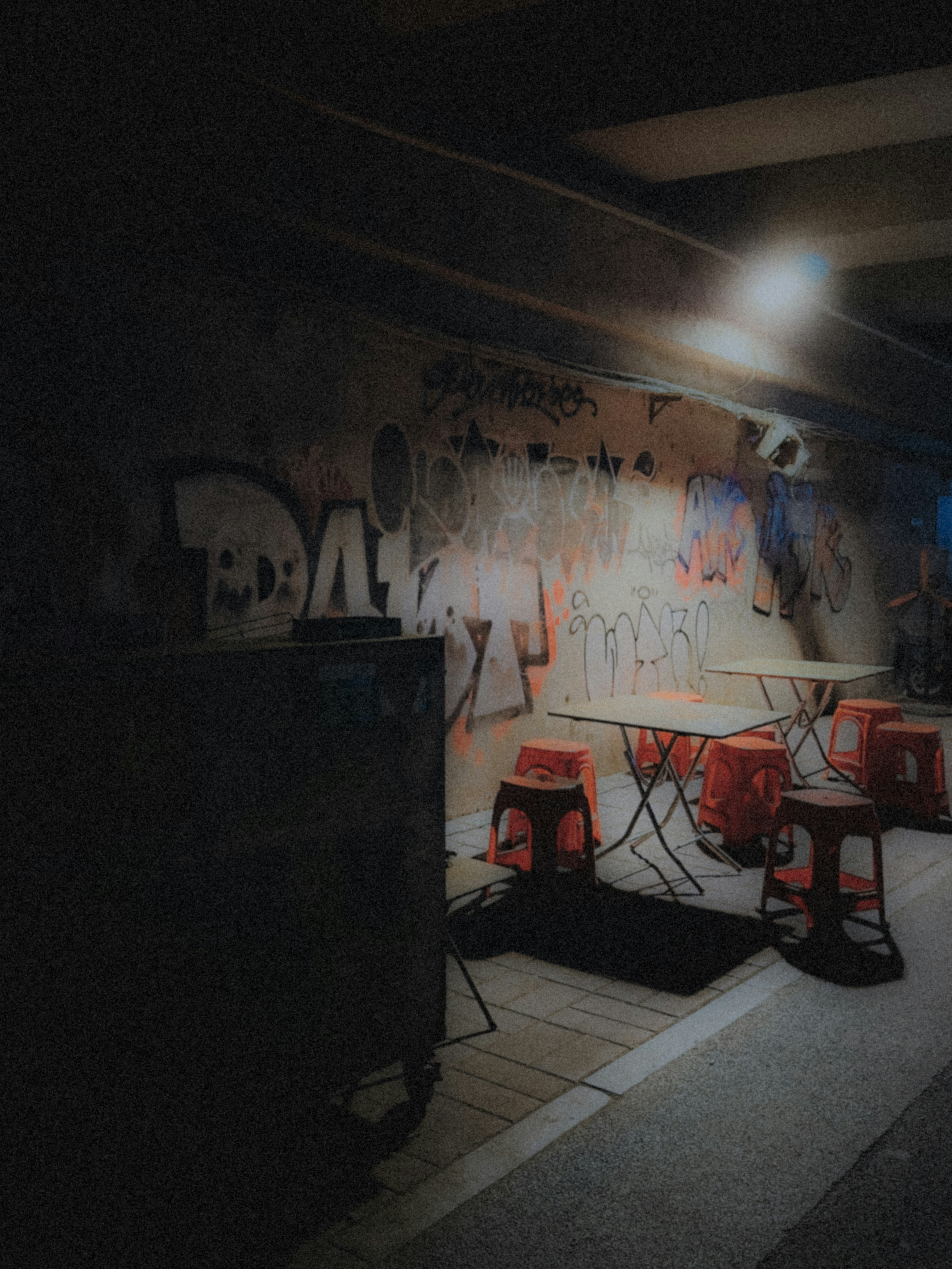 Under Neon Graffiti, A Quiet Night At The Tables