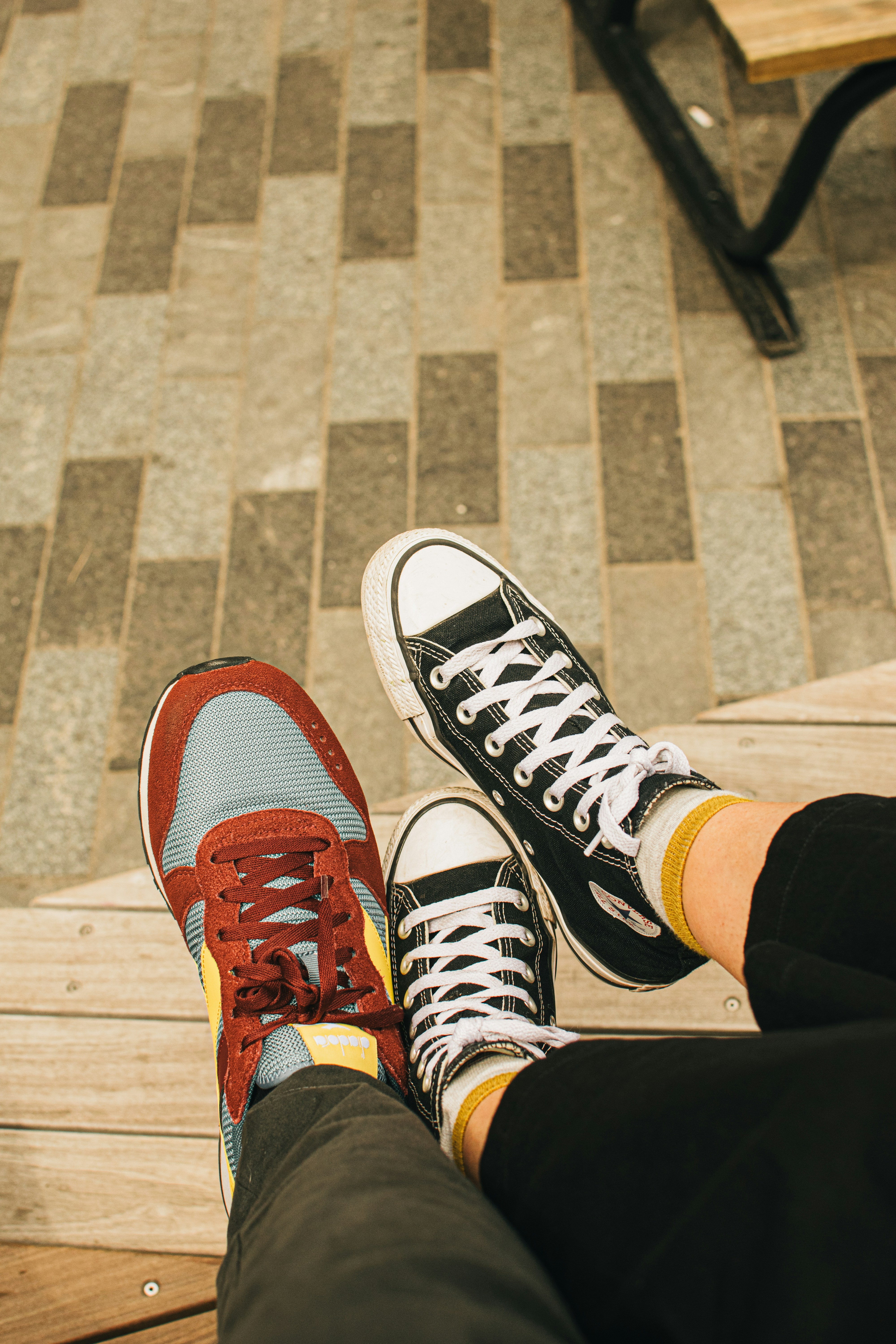 Two Kicks: A Pair of Sneakers Resting on Wood and Tile