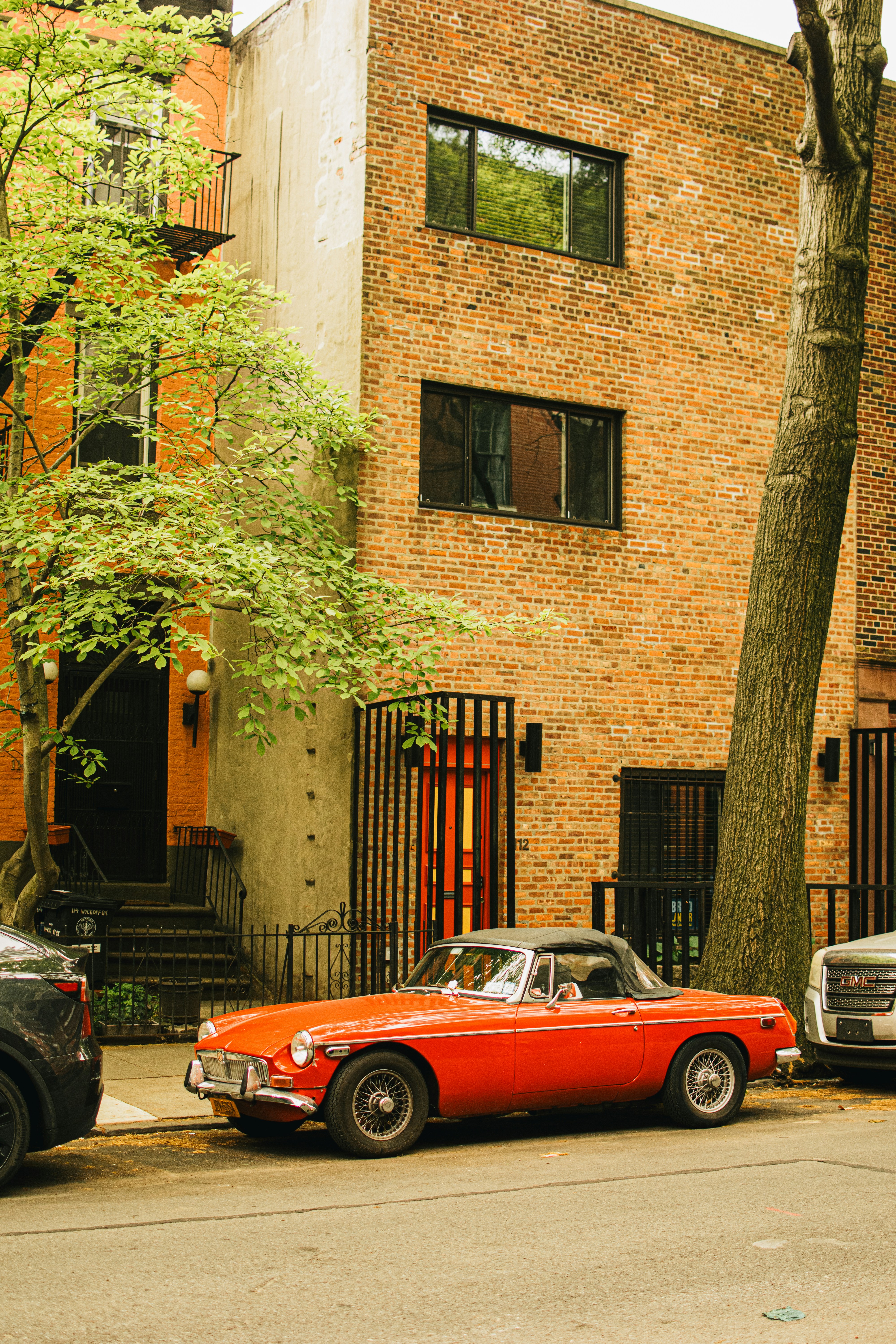 Red Triumph: A Vintage Convertible Resting by a Brick Urban Façade