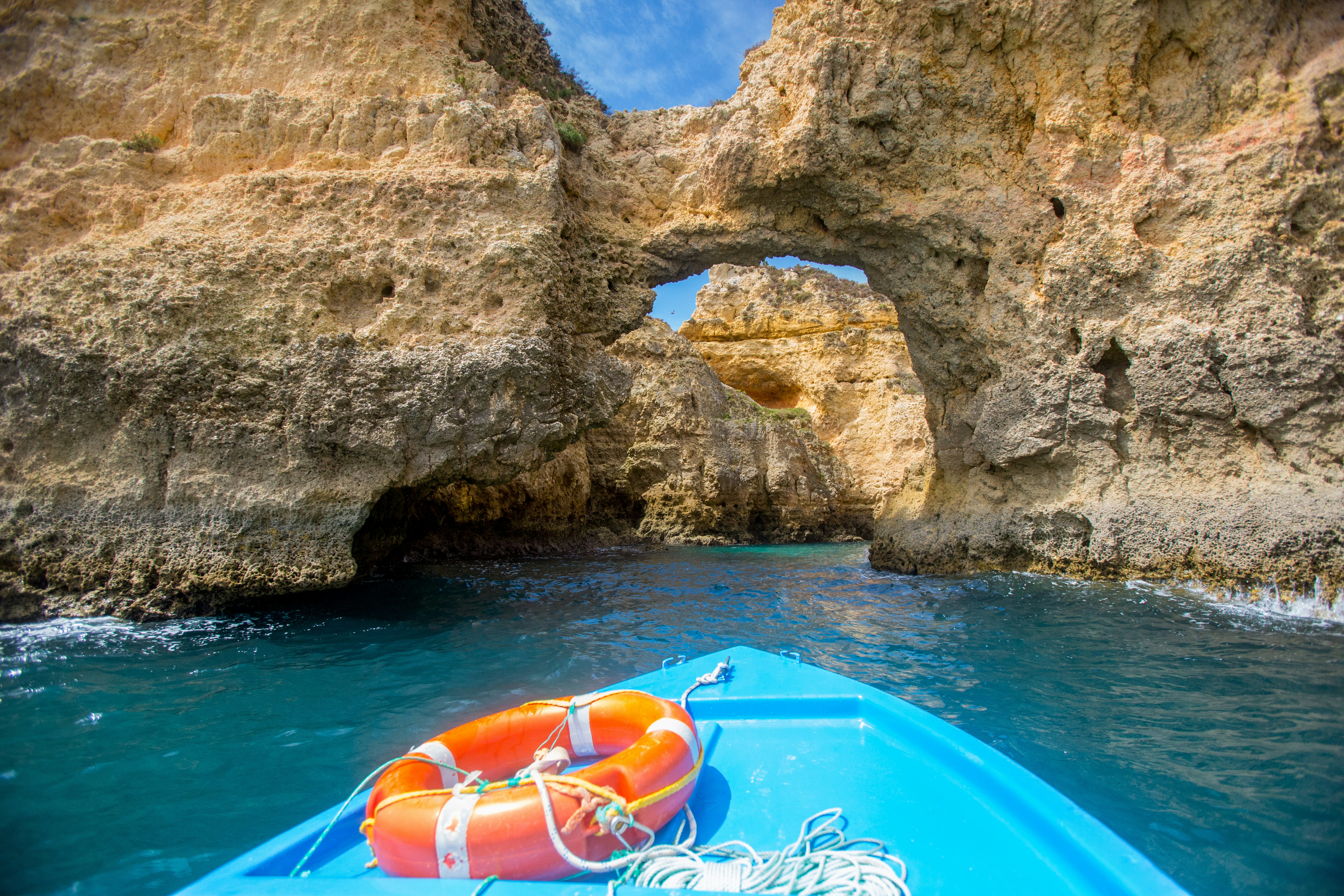 Blue Boat at a Bony Arch: Ocean Gap in Golden Cliffs
