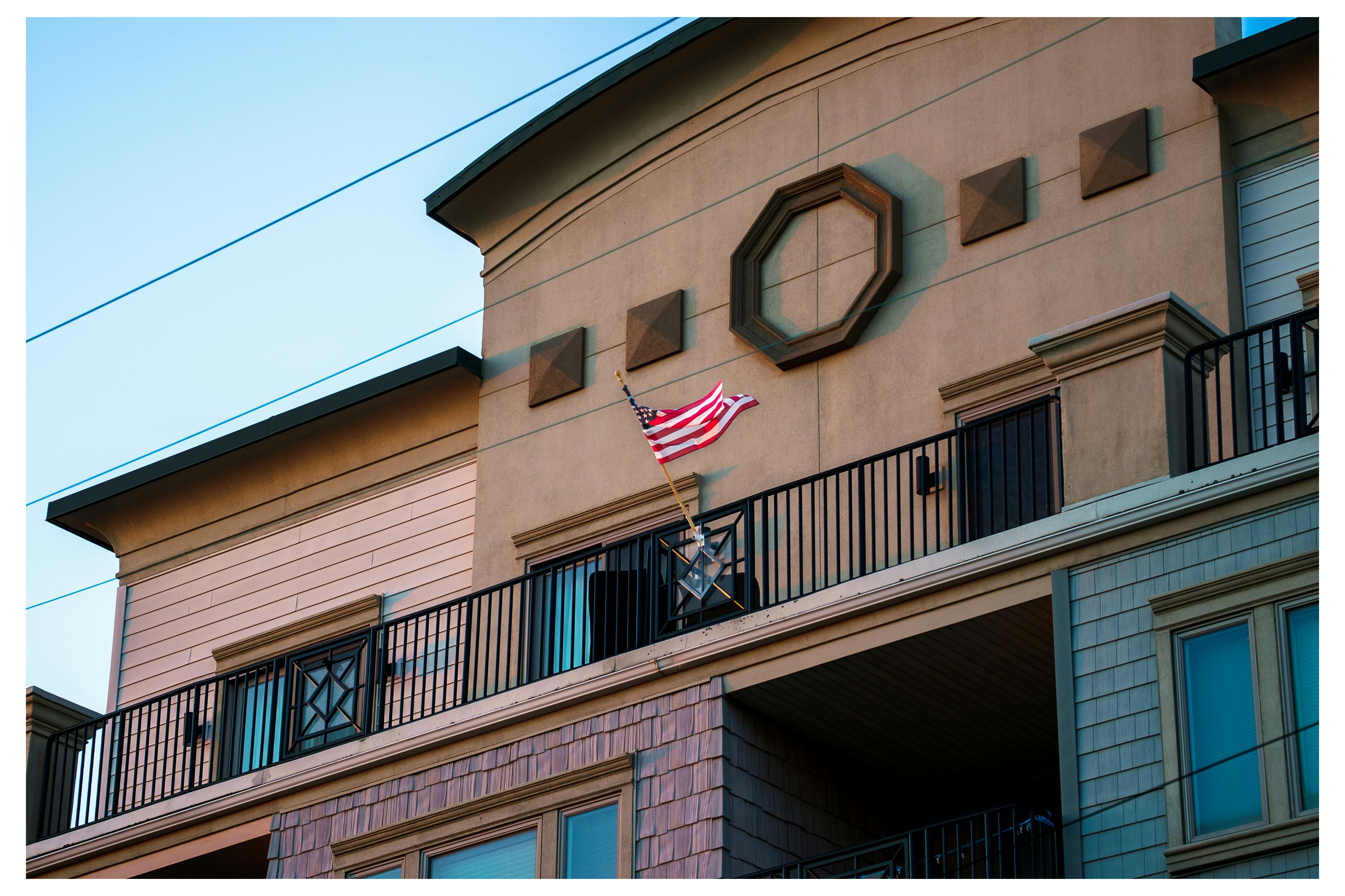 Flag Above the Hexagonal Architectural Emblem on a Modern Apartment Facade