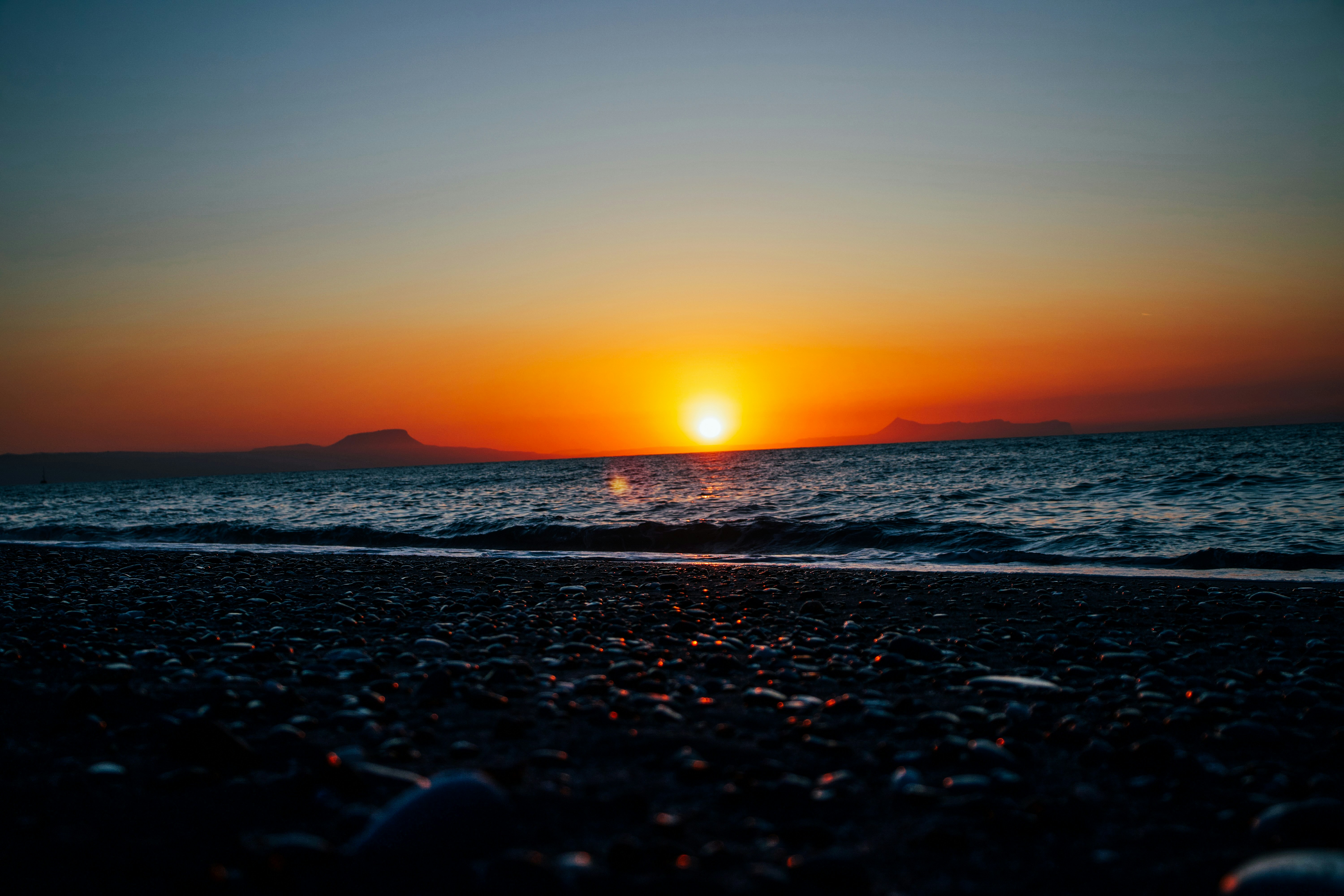 Quiet Horizon: Sunset Over Pebbled Shore