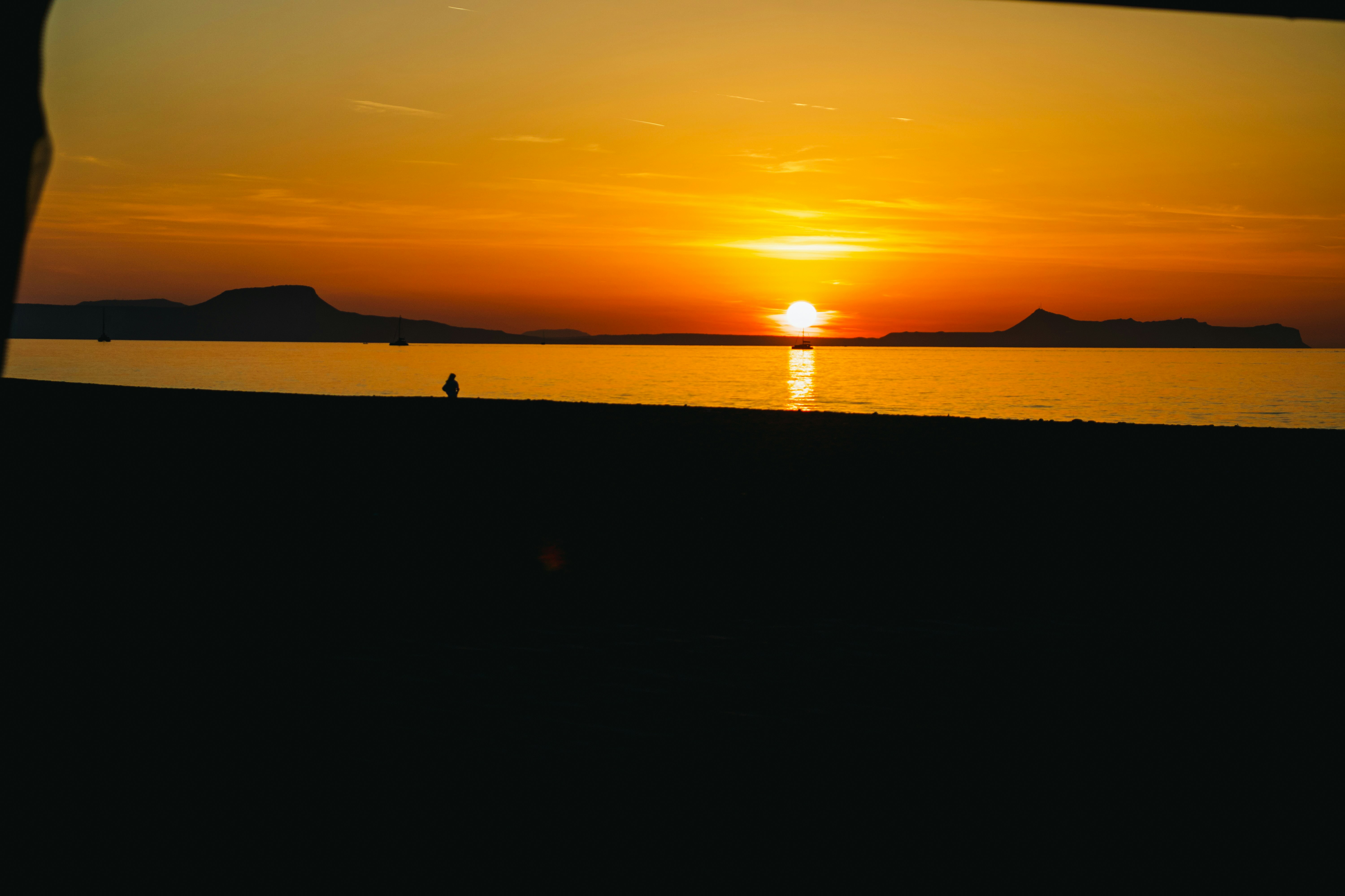 Sunlit Horizon: A Quiet Seaside Dusk with Silhouetted Figures