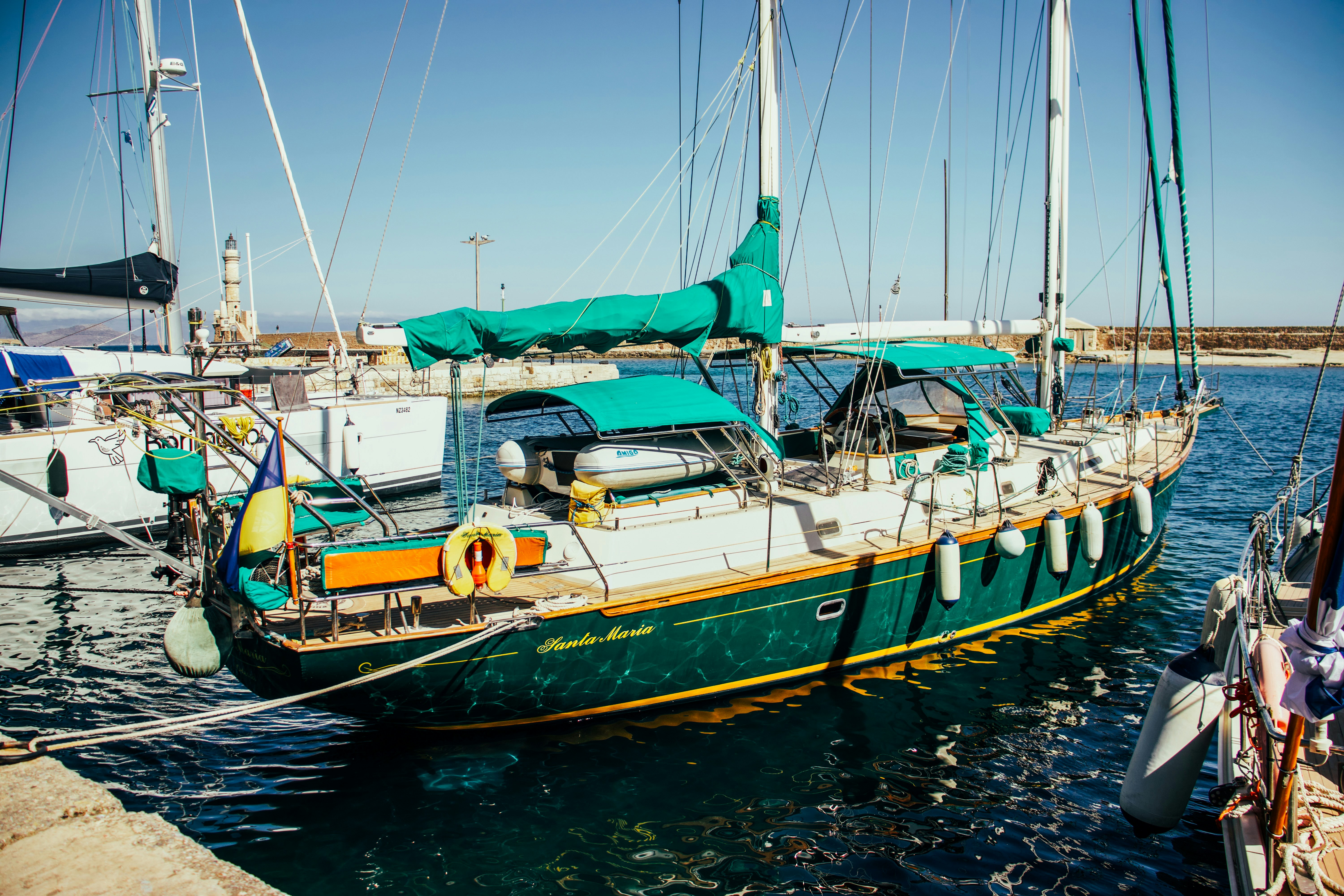 Sailboat at the Marina: Sunlit Vessel with Teal Canvas Docked at Dusk