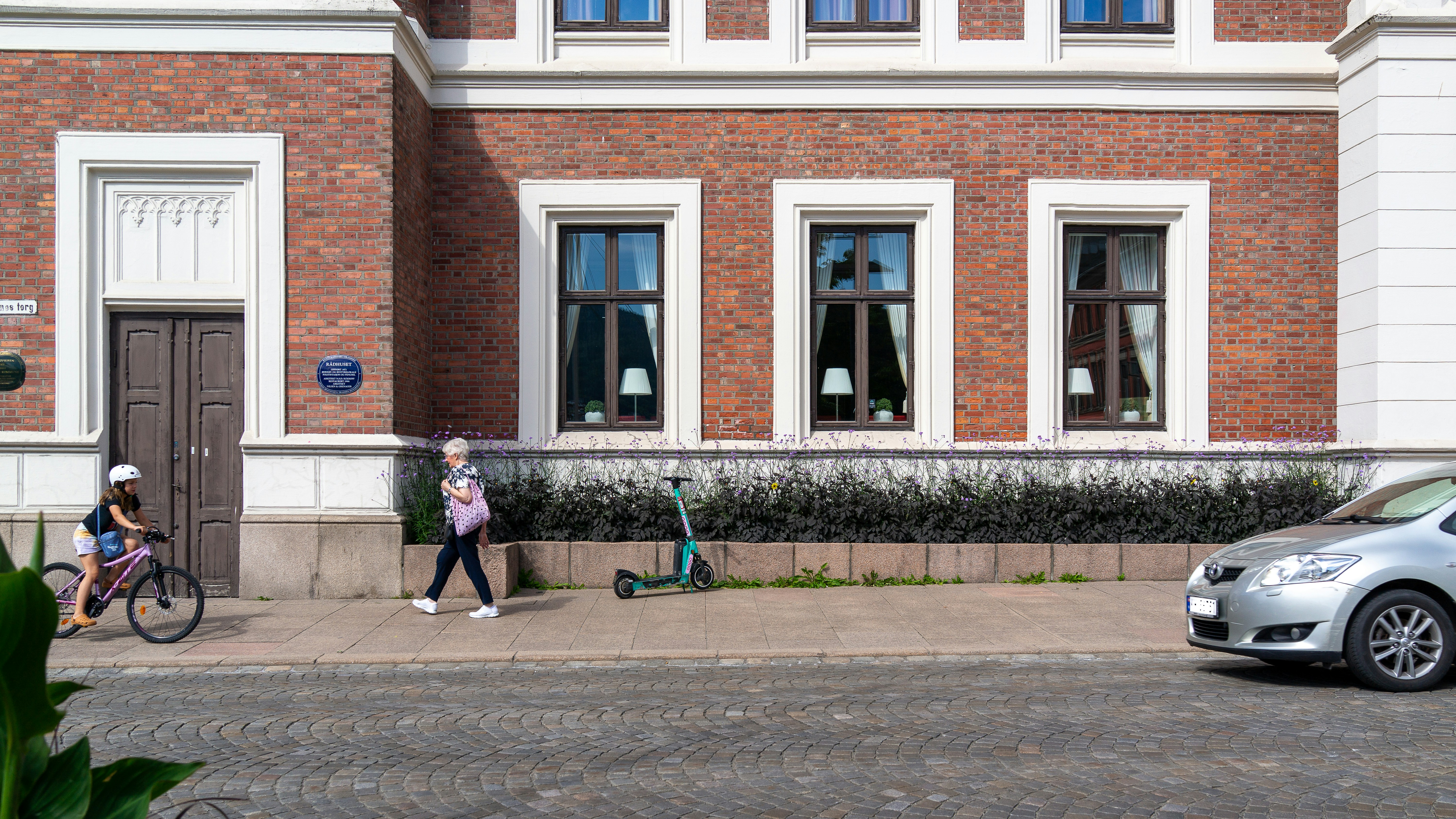 Urban sidewalk ballet: a quiet moment along a brick façade