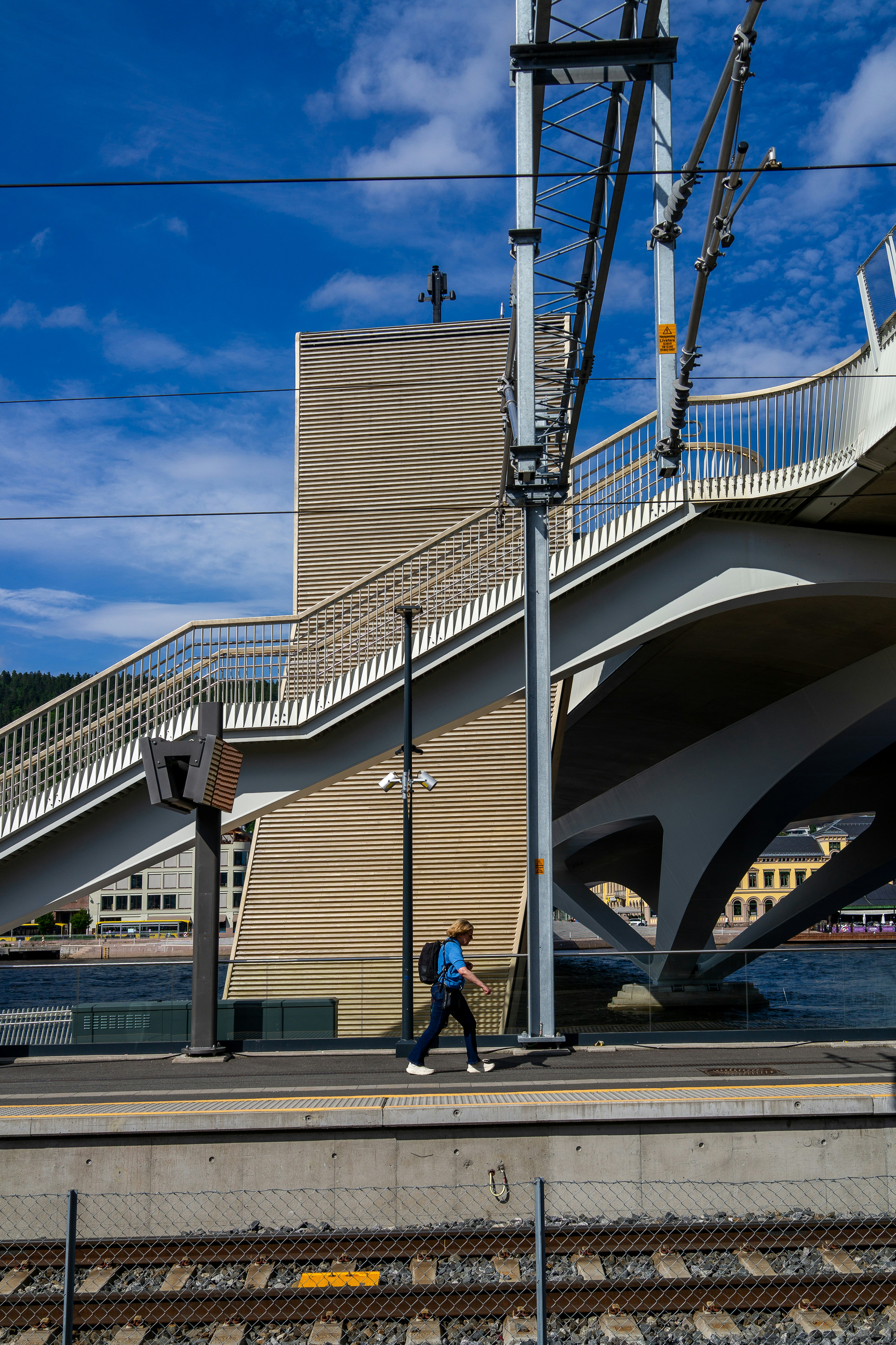 Runner under the modern bridge: a lone traveler crosses urban architecture