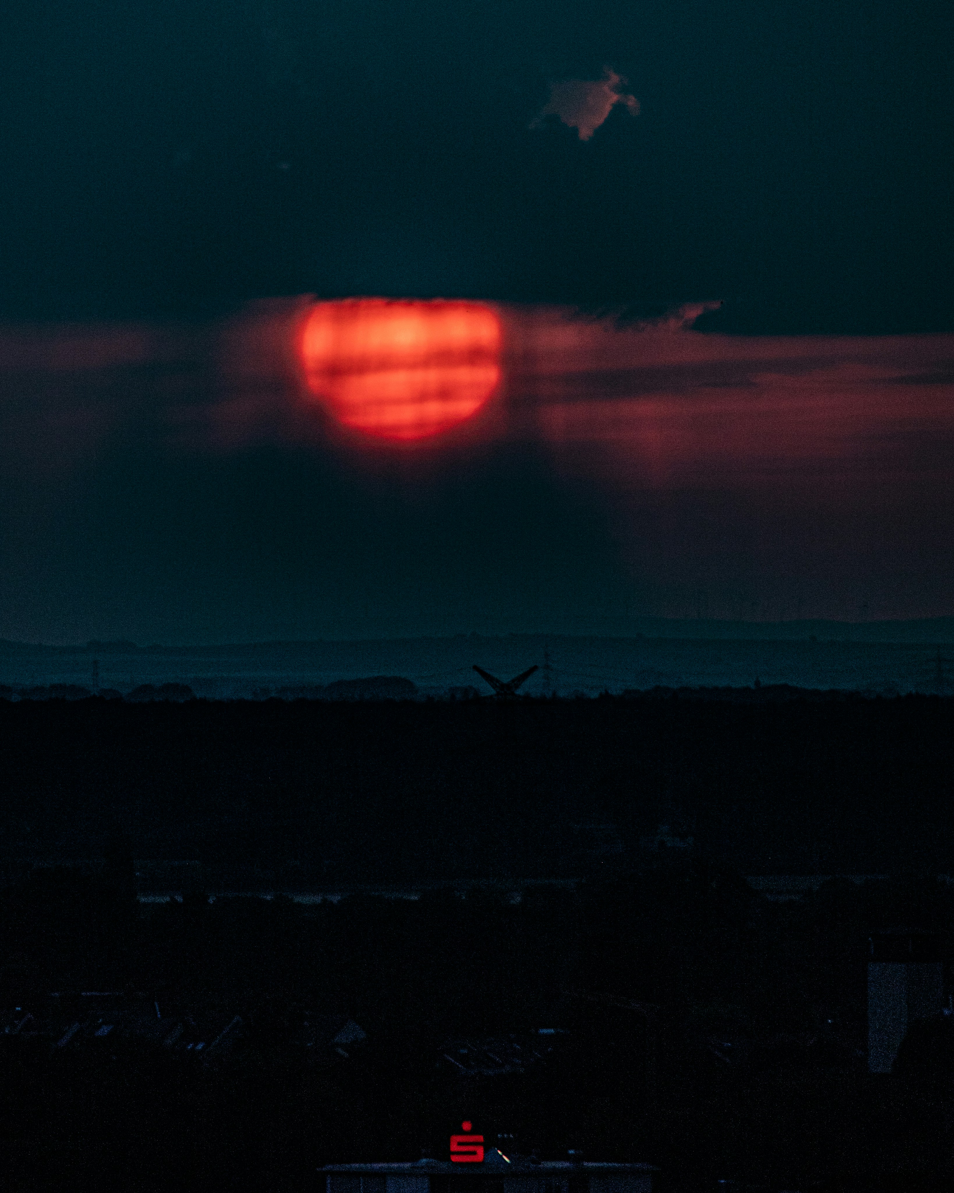 Crimson Horizon: Sun Dips Behind a Distant Ridge
