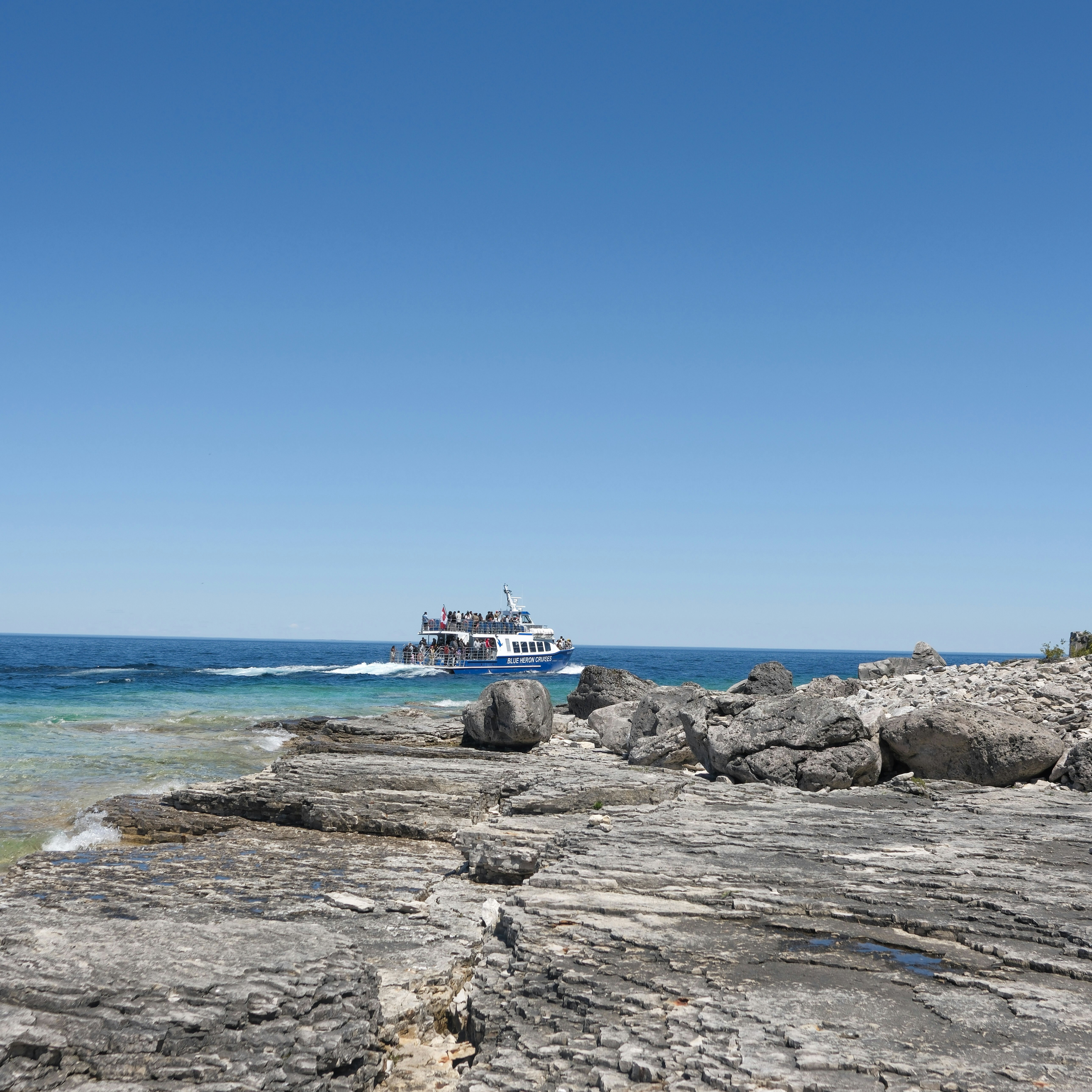 Coastal Vessel Crossing: A Quiet Sea Near Weathered Rocks