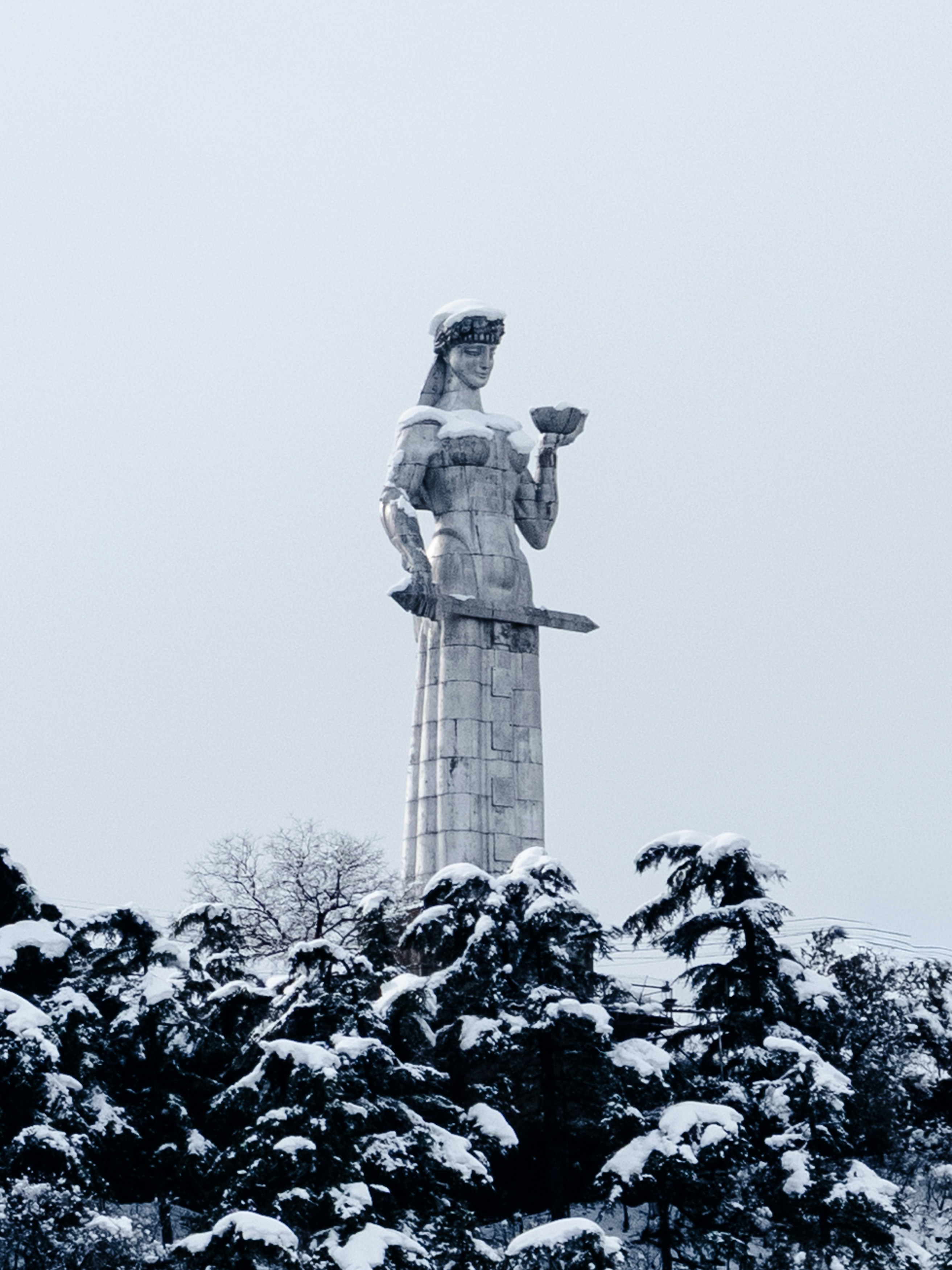 Snowbound Colossus: A Frosted Statue Reaching Toward Winter Sky