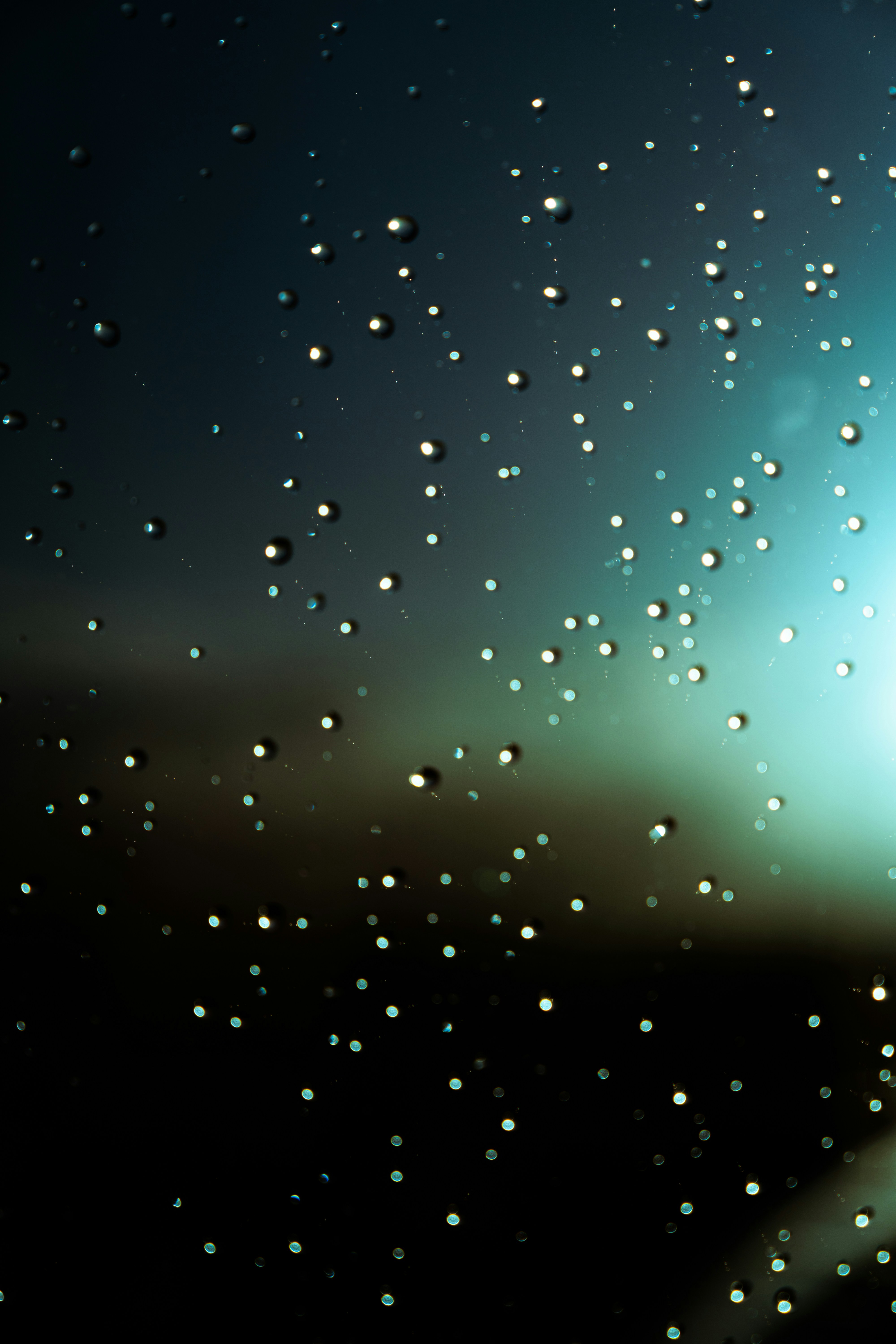 Raindrops on glass with a blurred blue background.