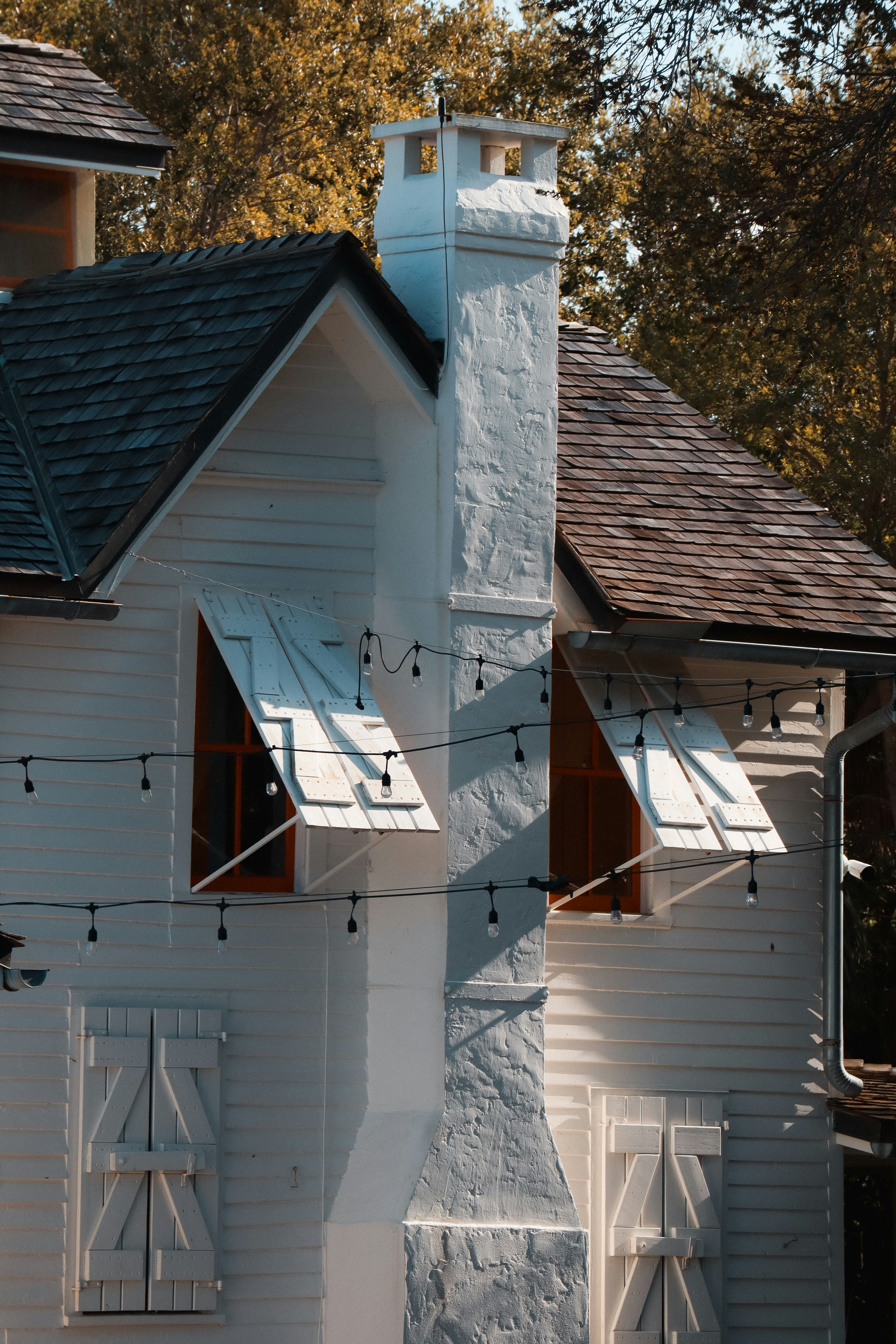 Chimney Central: White House with String Lights and Shuttered Windows