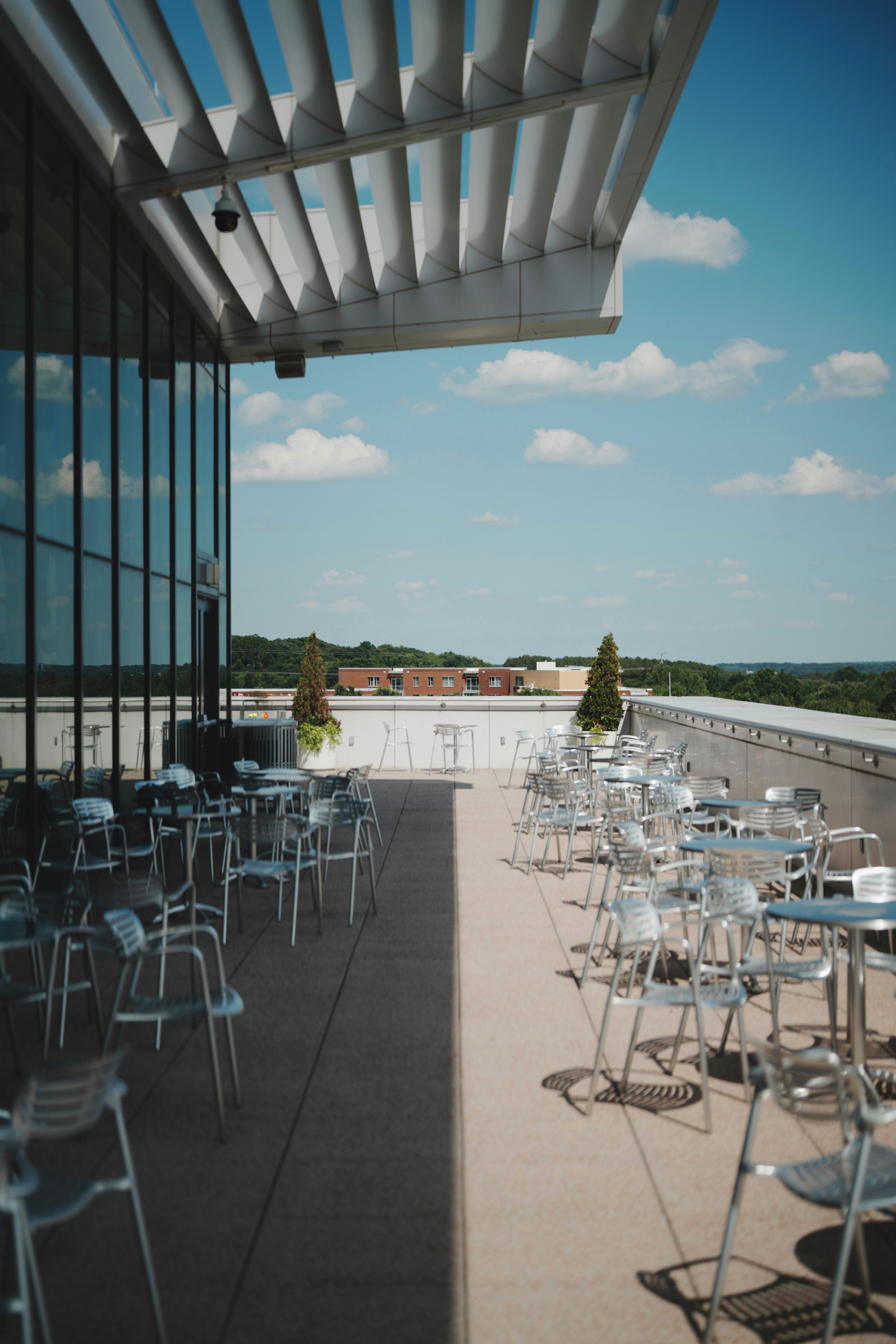 Rooftop Café Terrace: Sunlit Chairs and Modern Overhang