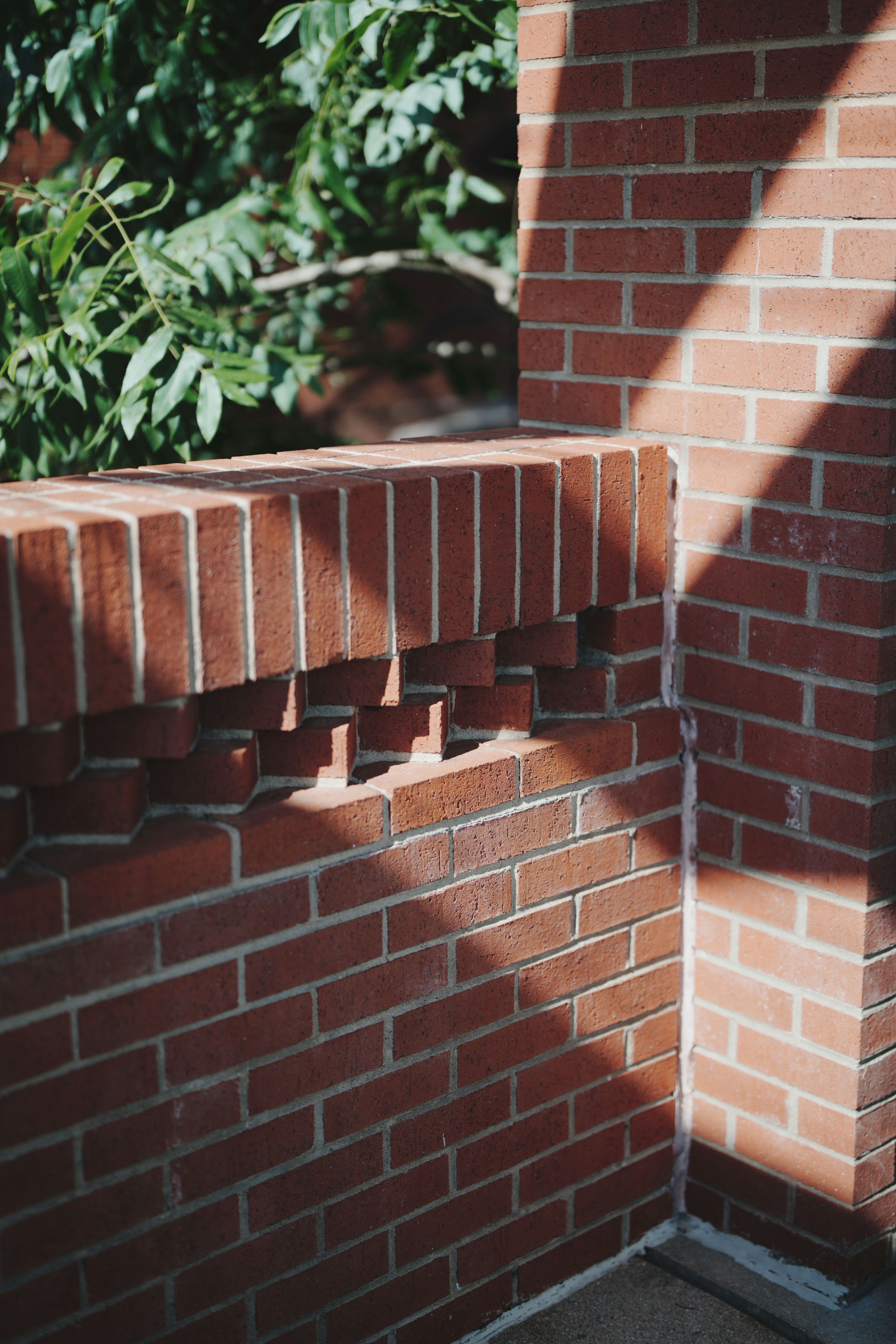 Sunlit Brick Corner: Shadowed Edges and Greenery