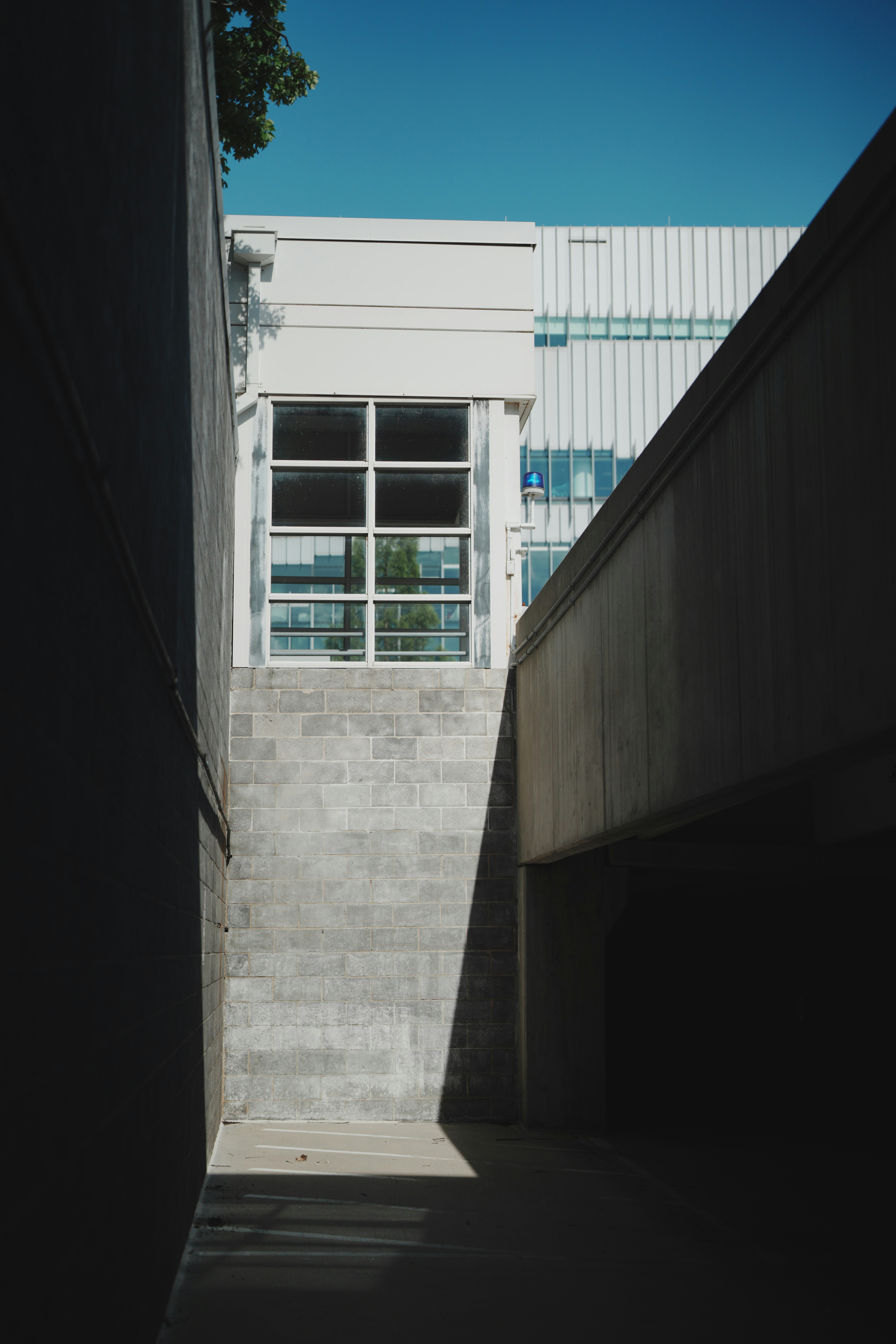 Between Walls: Sunlit Gap and Glass Window Above Concrete