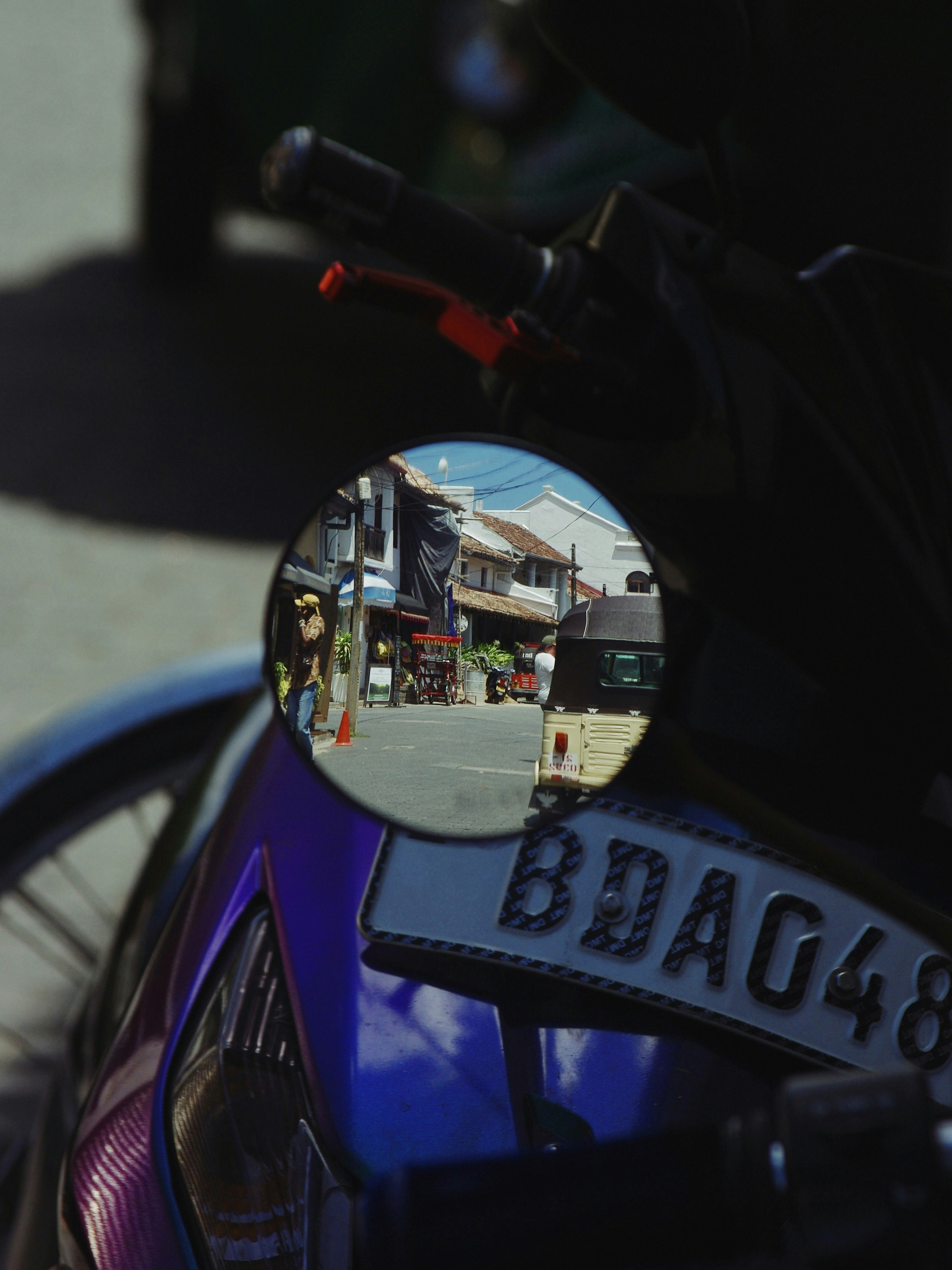 Reflection in the Bike Mirror: Street Scene Framed by Chrome and License Plate