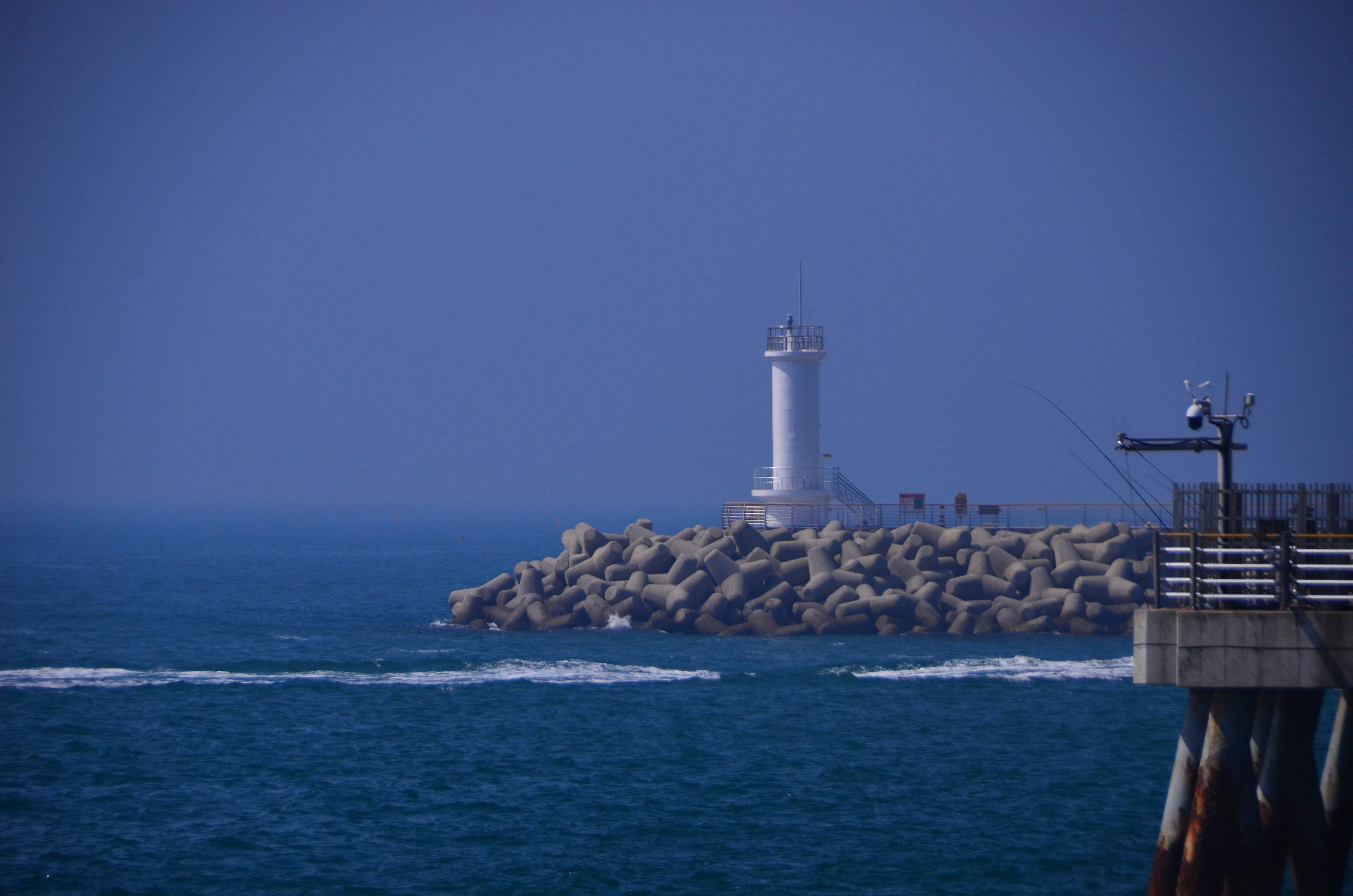 Lighthouse Watch from a Piered Edge Across the Sea