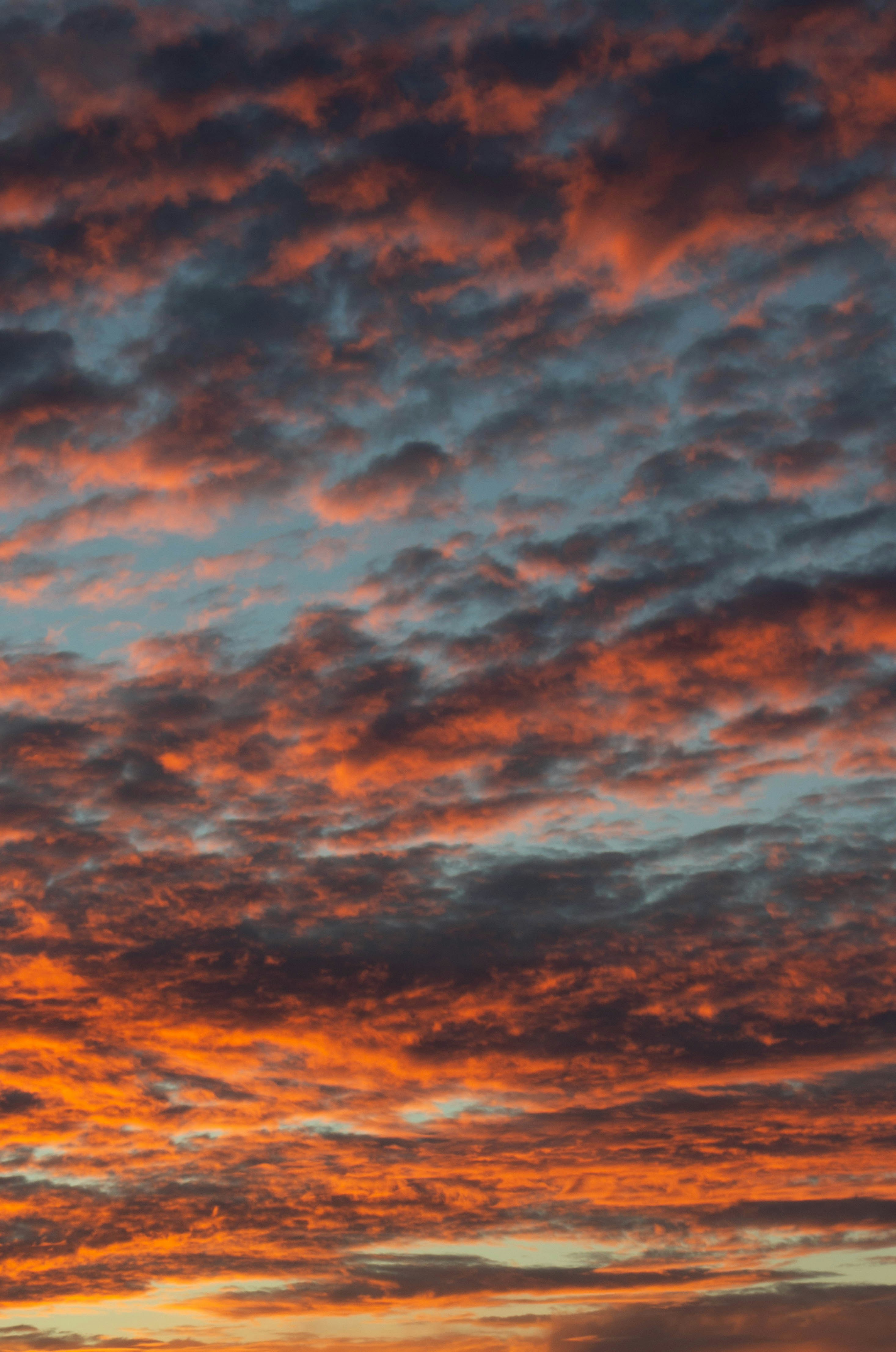 Vibrant sunset clouds span the sky with warm orange and cool blue tones, painting a dramatic horizon. The image highlights expansive cloud textures and gradient lighting.