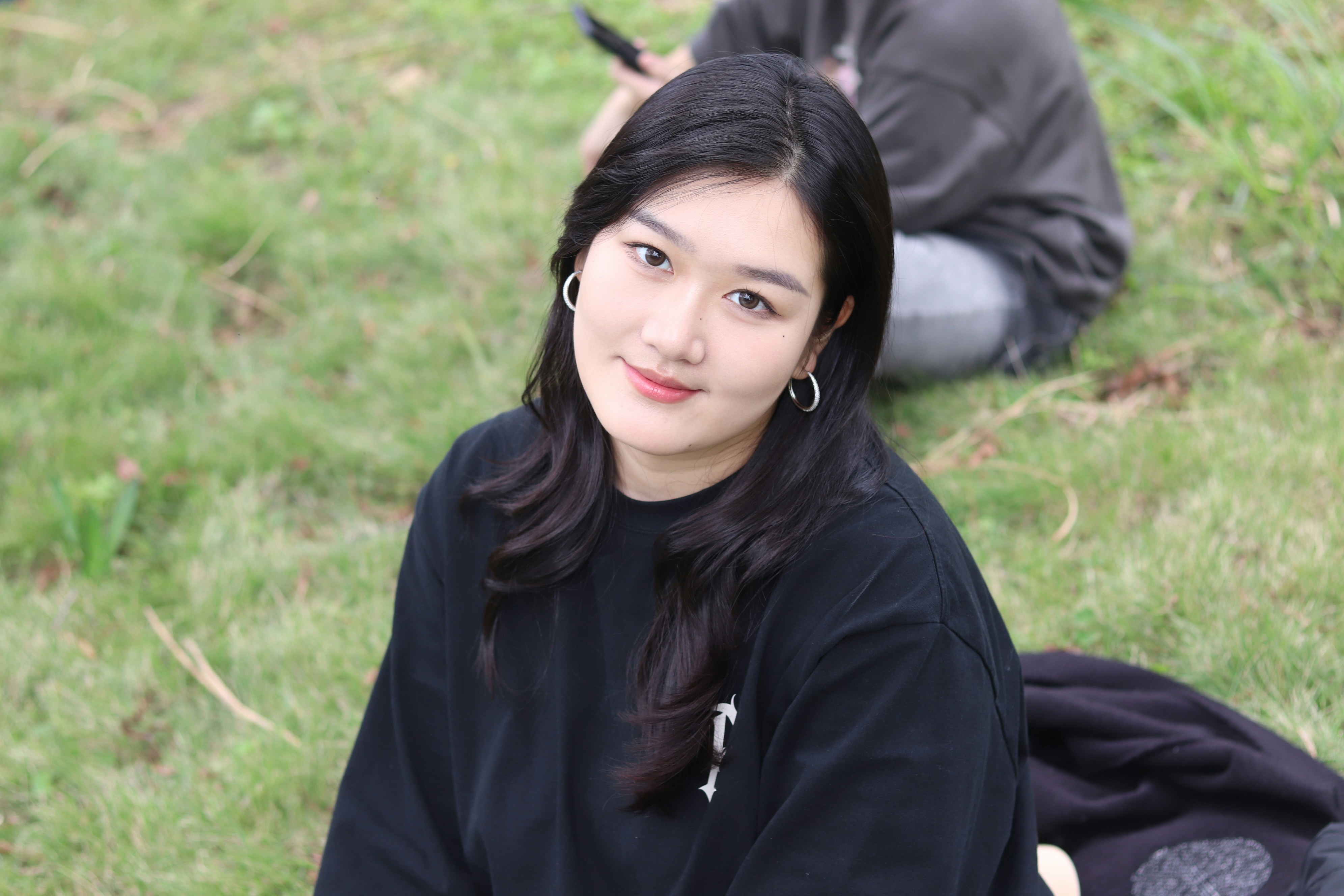 Soft portrait of a calm young woman sitting on the grass
