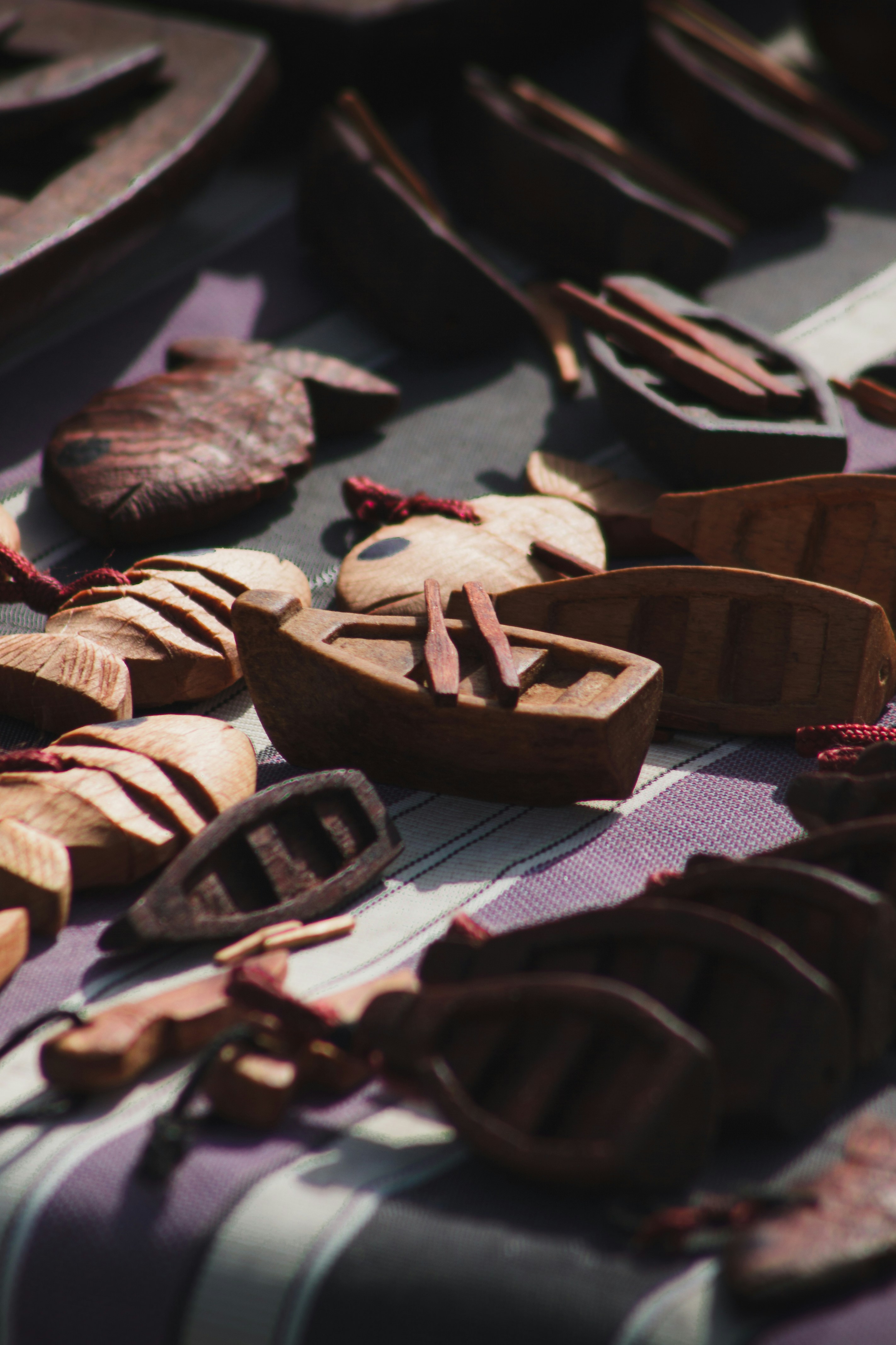 Carved wooden trinkets spill across a striped cloth, catching light and shadow