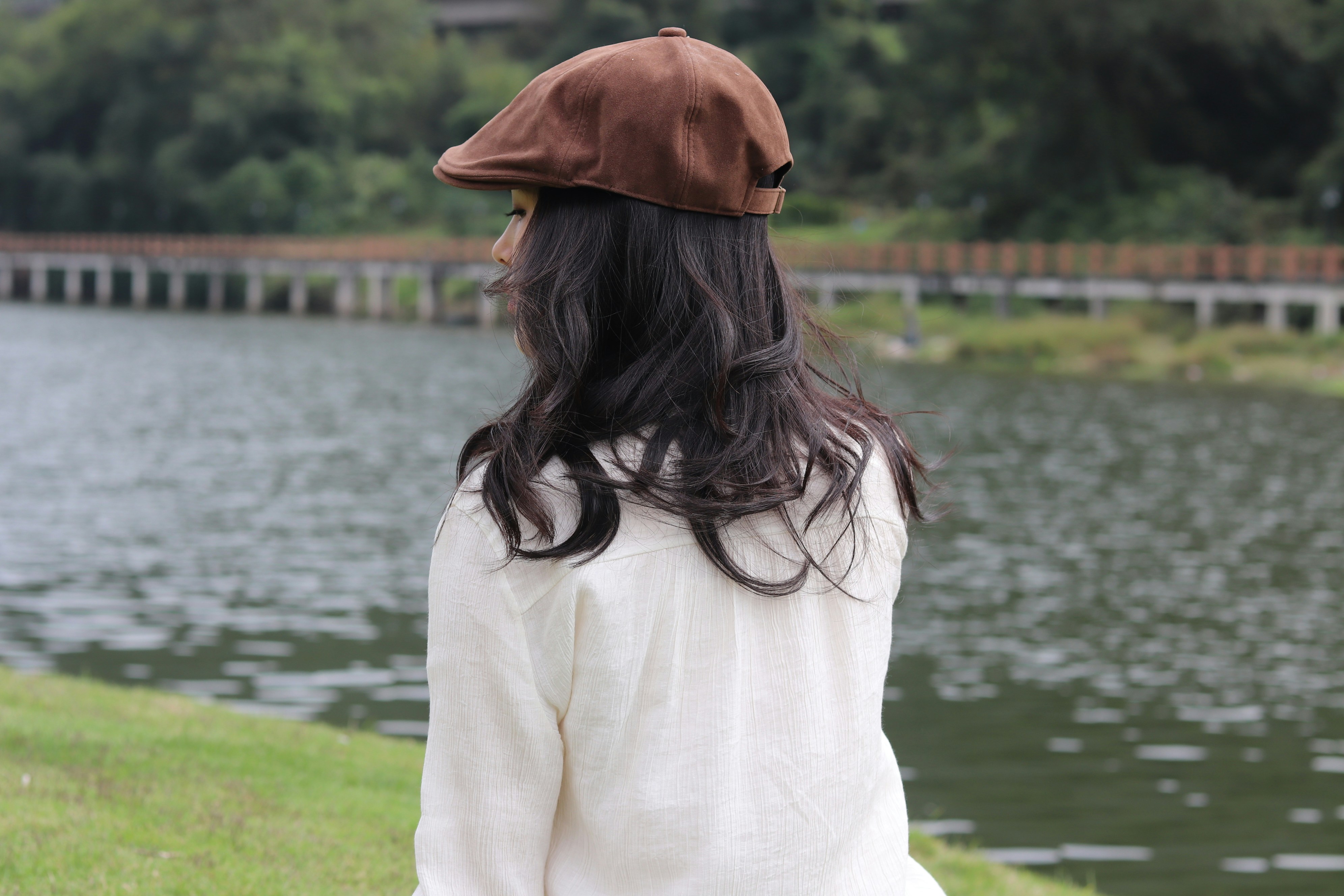 Curtain of dark curls and a brown beret by the lakeside