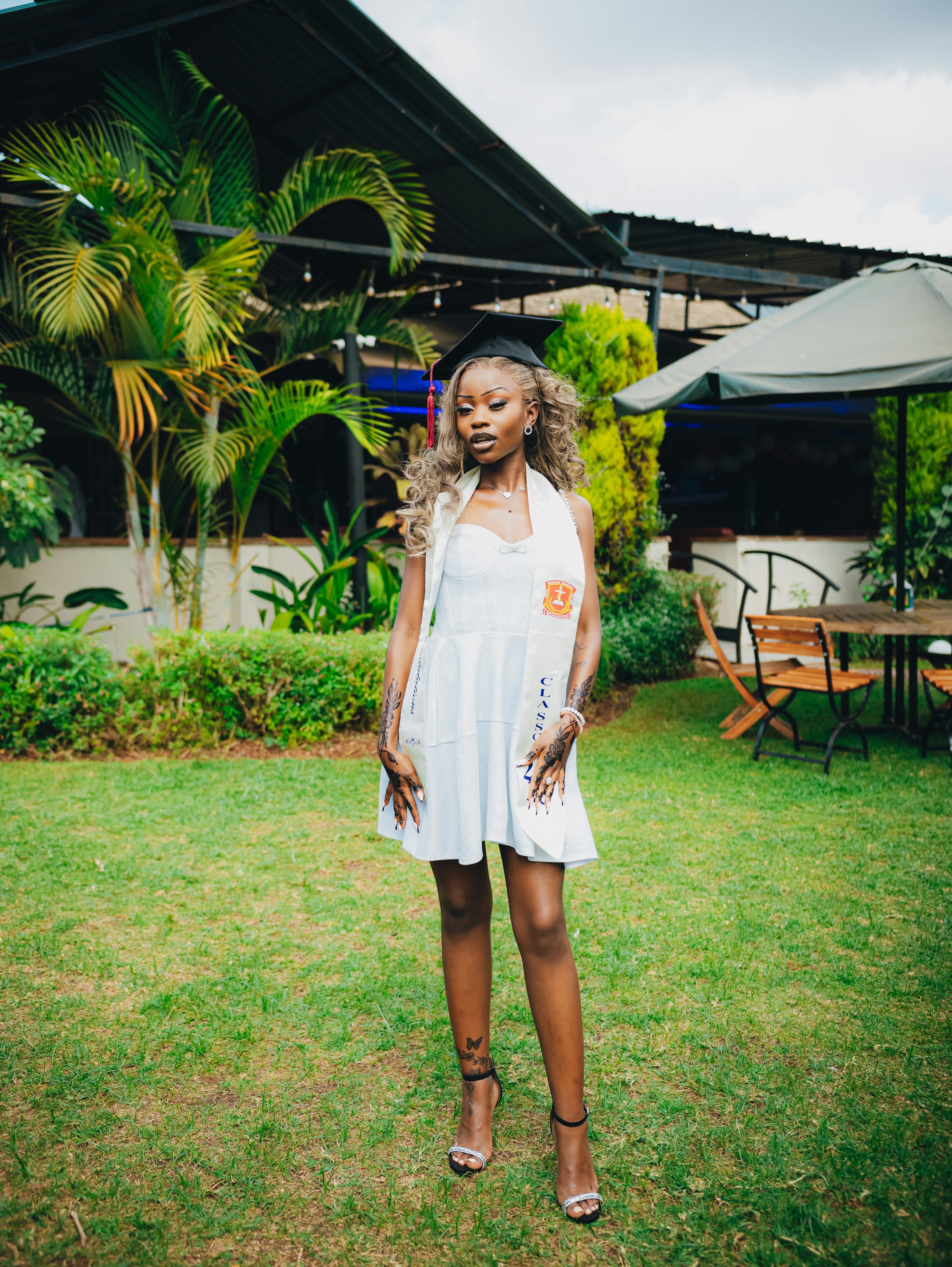 Cap and gown on the lawn: a graduate posing in a sunlit courtyard