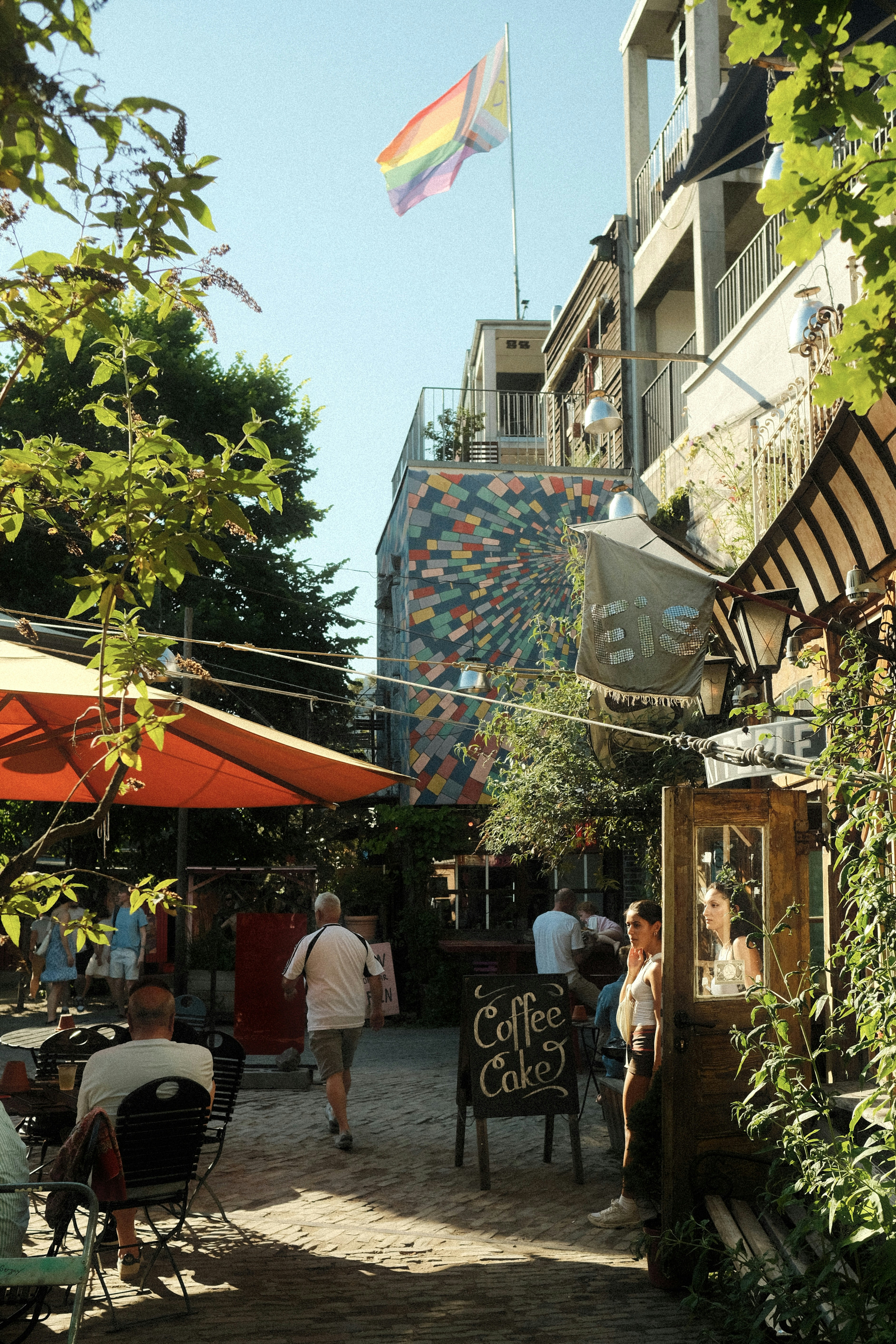 Sunlit Alley Café Under a Rainbow Flag