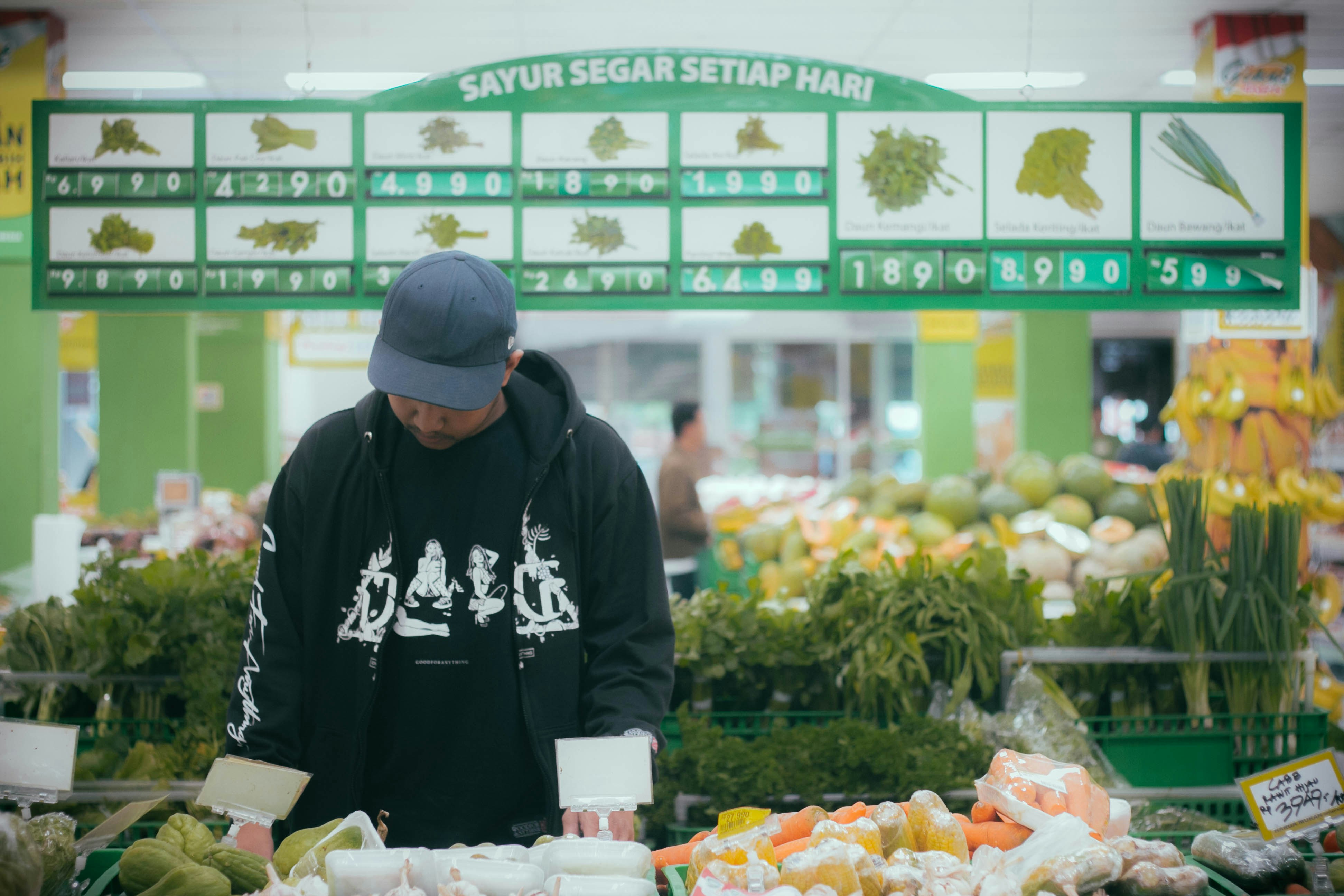 Market Vendor in a Colorful Produce Aisle Under Green Signage