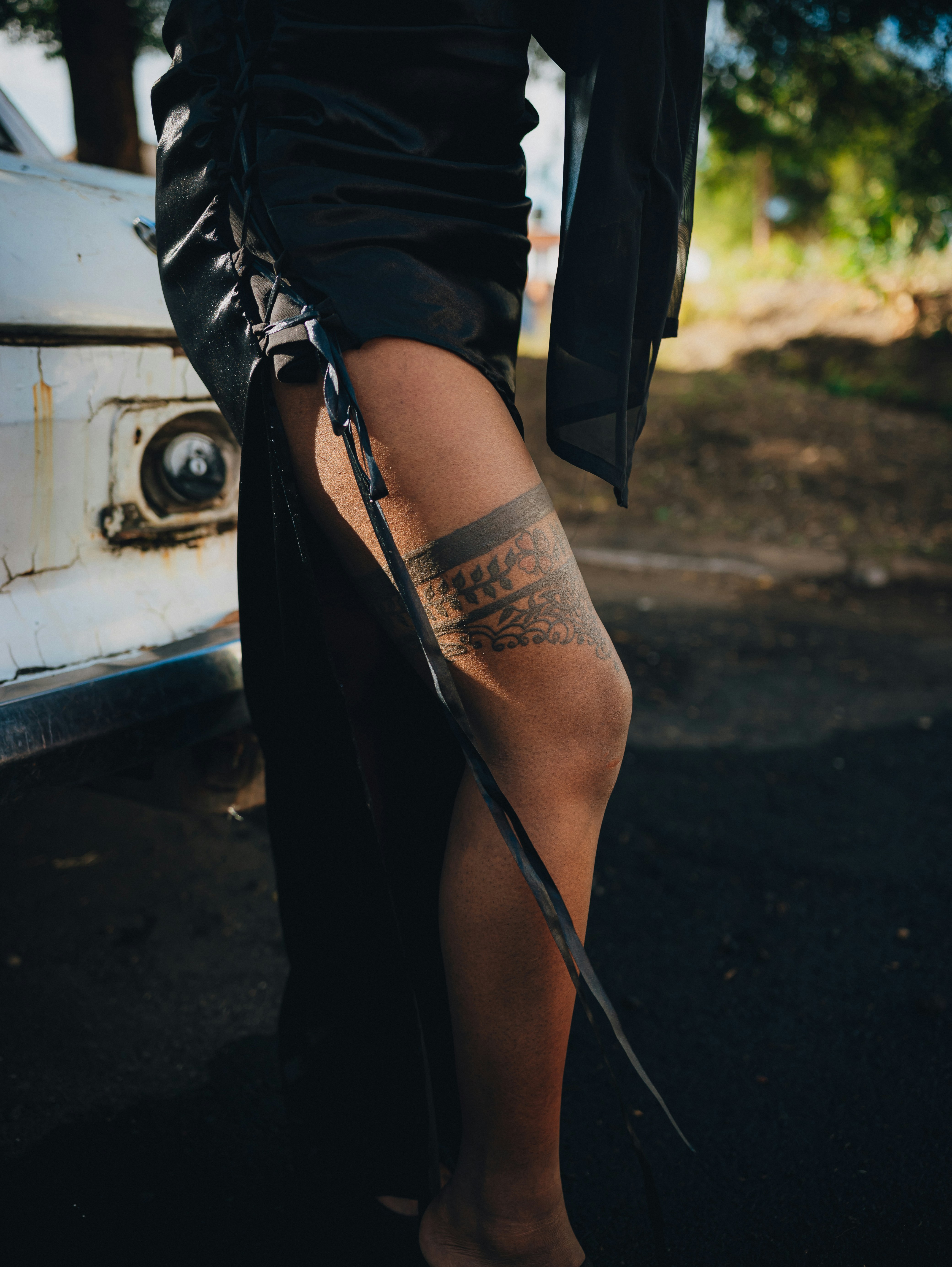 Tattooed Leg in a Strappy Dress by a Weathered Car