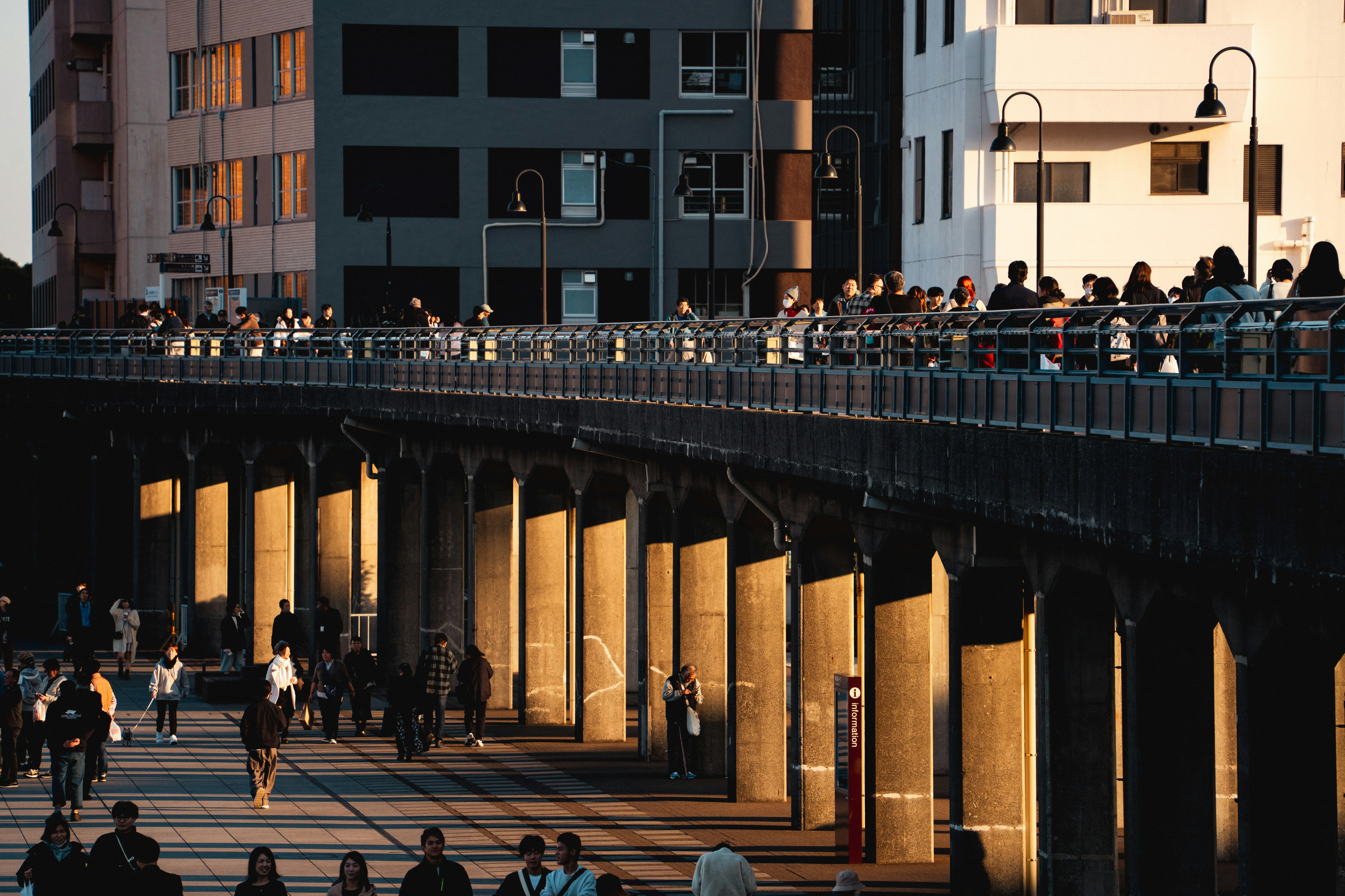 Footbridge Afterglow: People Stroll Under Arches at Dusk