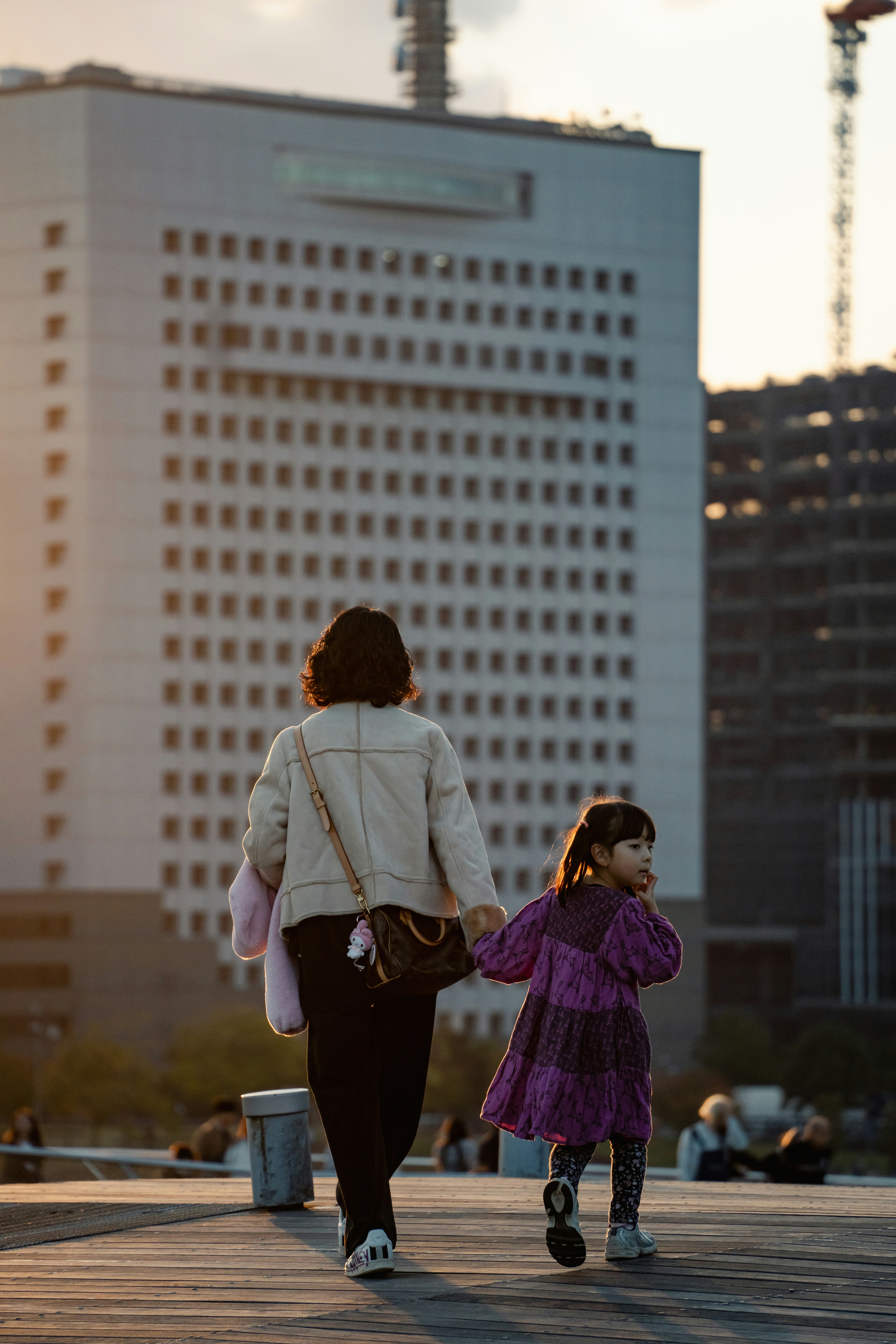 Evening Stroll: A Mother and Daughter Walk Toward the City Lights