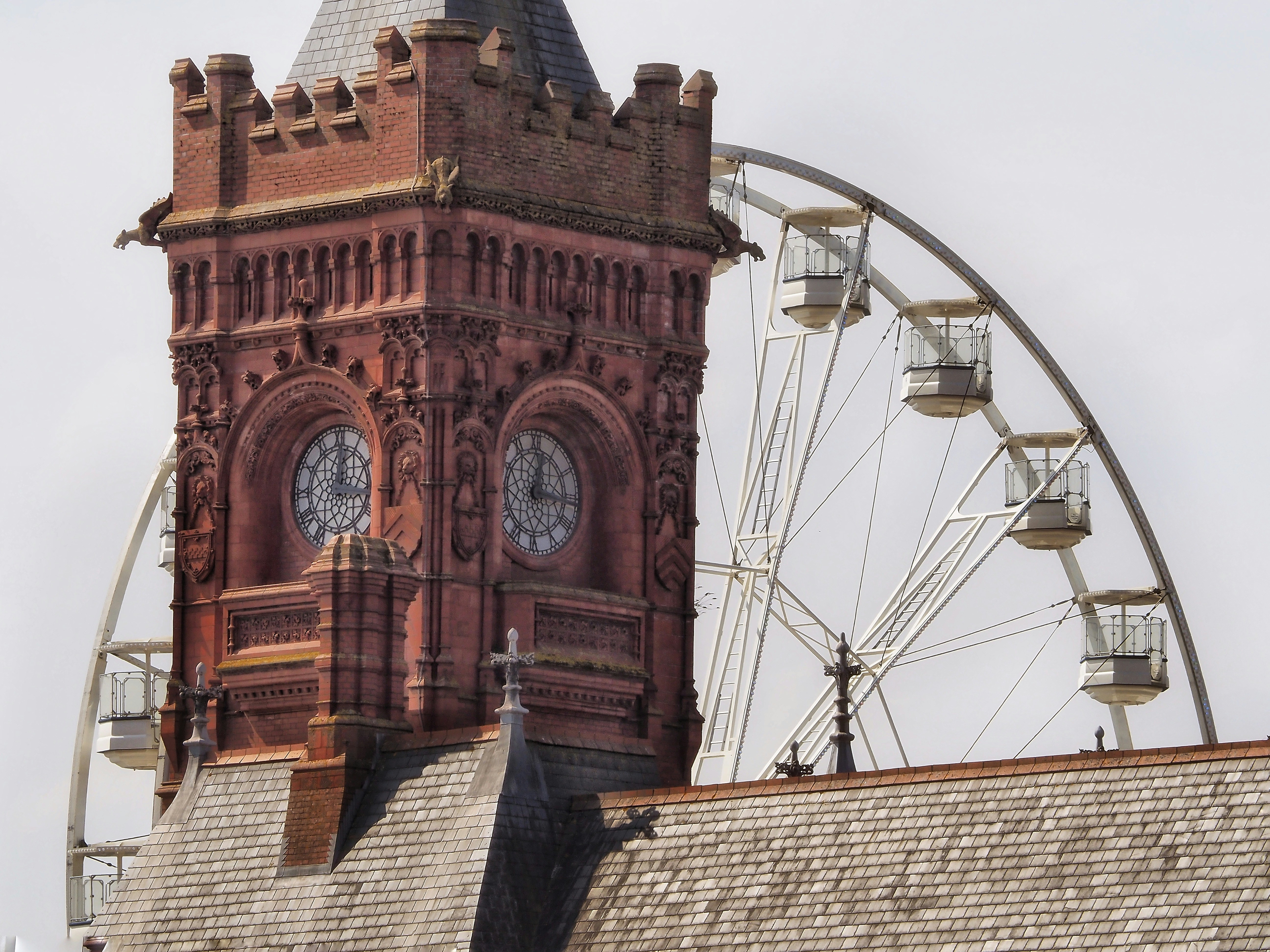 Towering Clock and Wheel: Red Brick Architecture Framing a Ferris Wheel