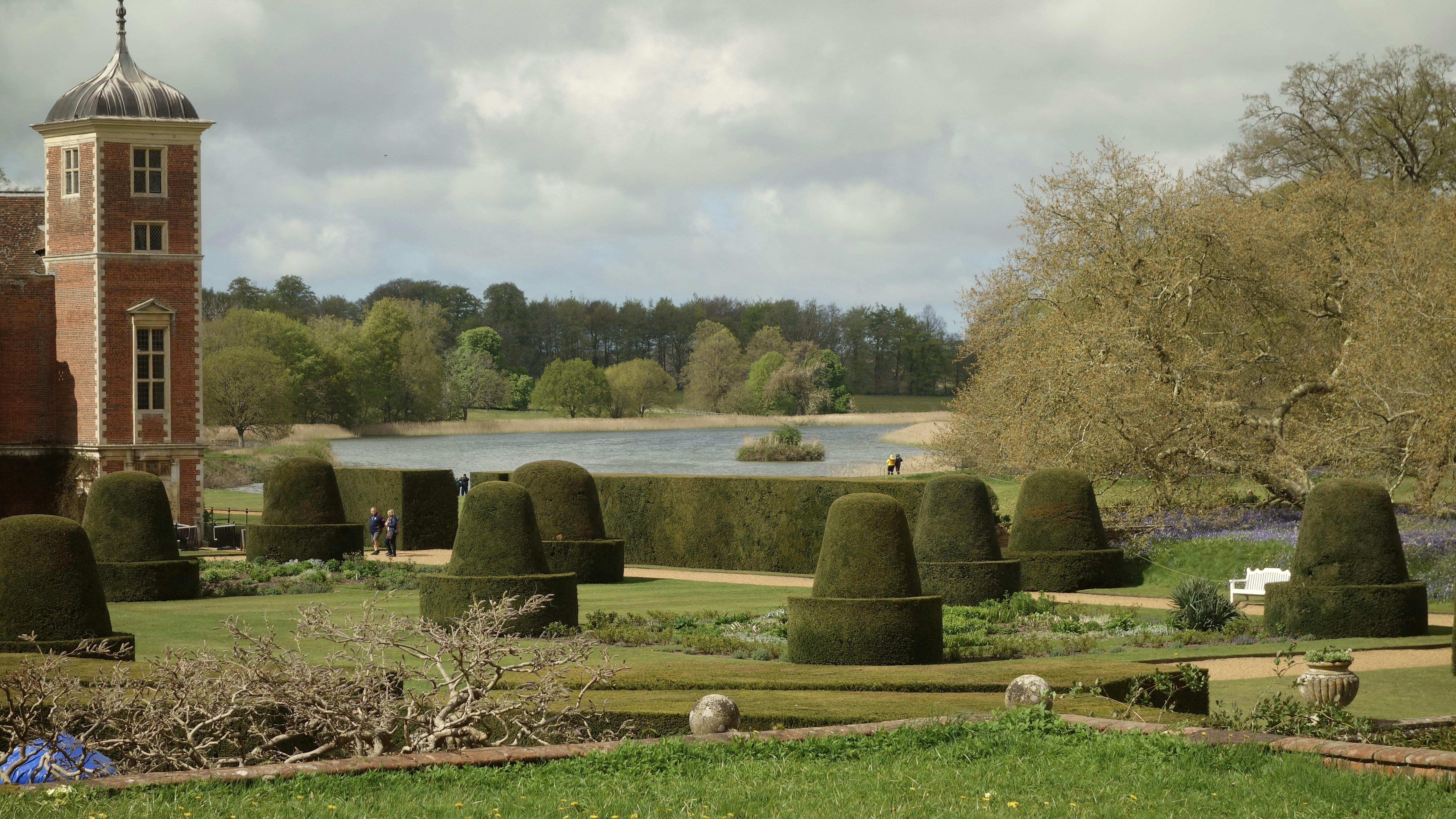 Regal Gardens by the Lake: Sculpted Hedges and a Red Brick Tower