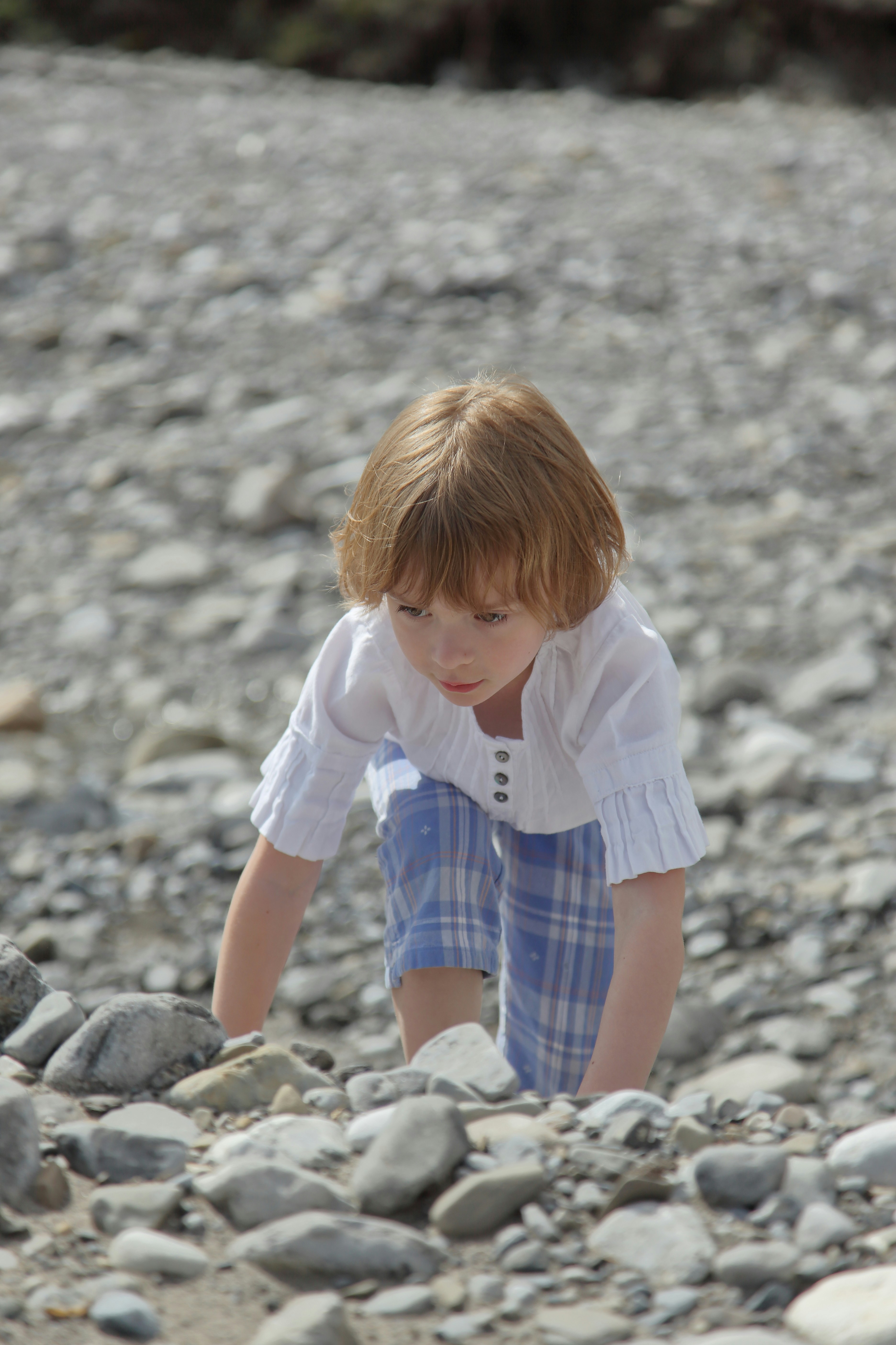 Child exploring a rocky shoreline in soft daylight
